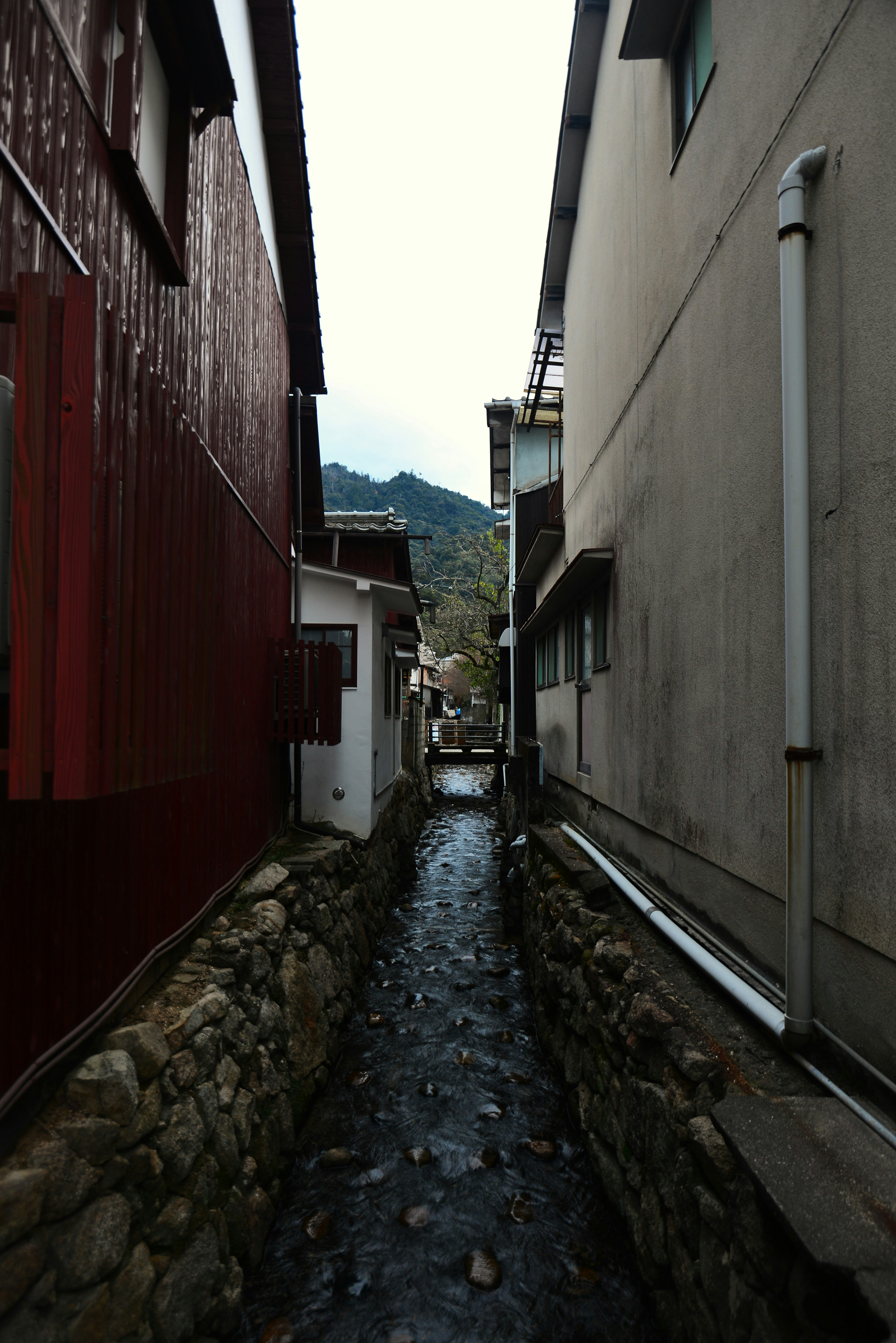 Canal Between Timeworn Walls: A Narrow Urban Waterway Toward the Mountain Horizon