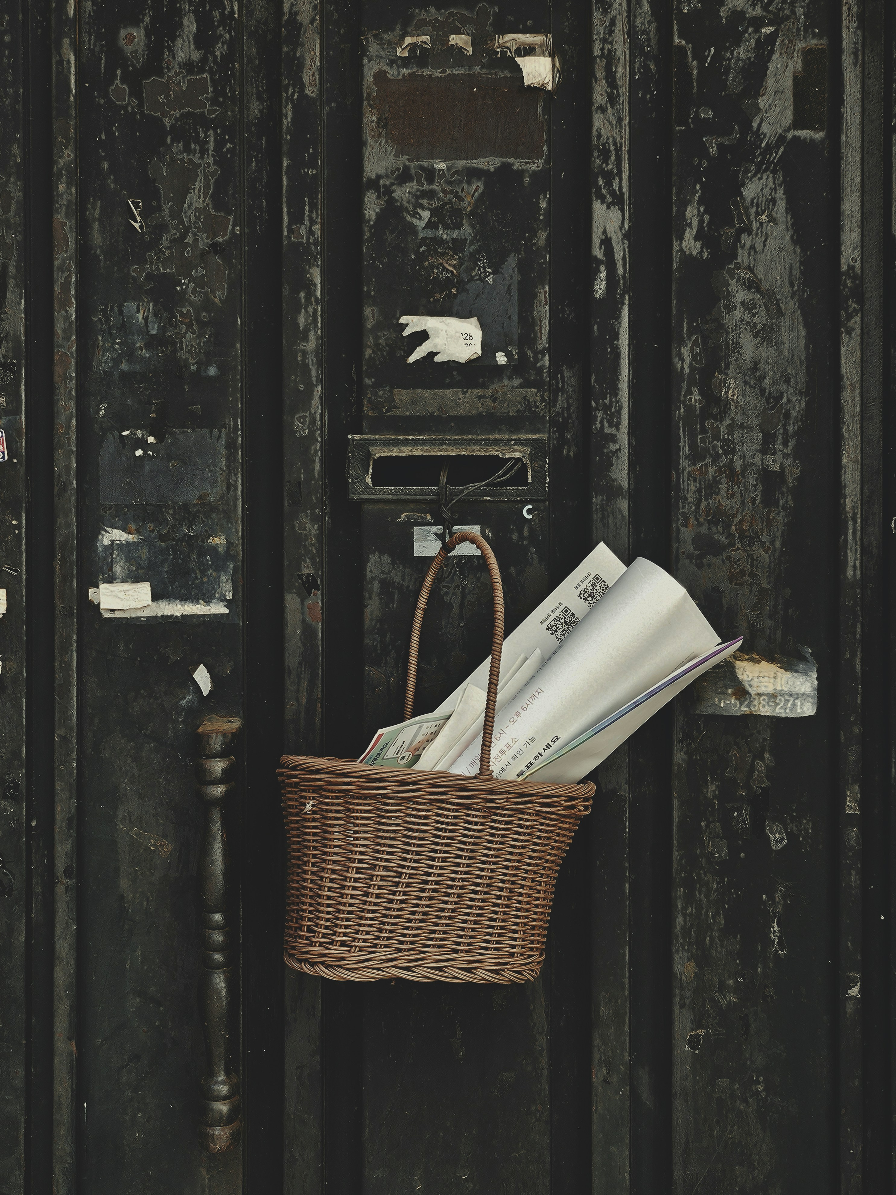 Newspapers fill a basket on a weathered door.