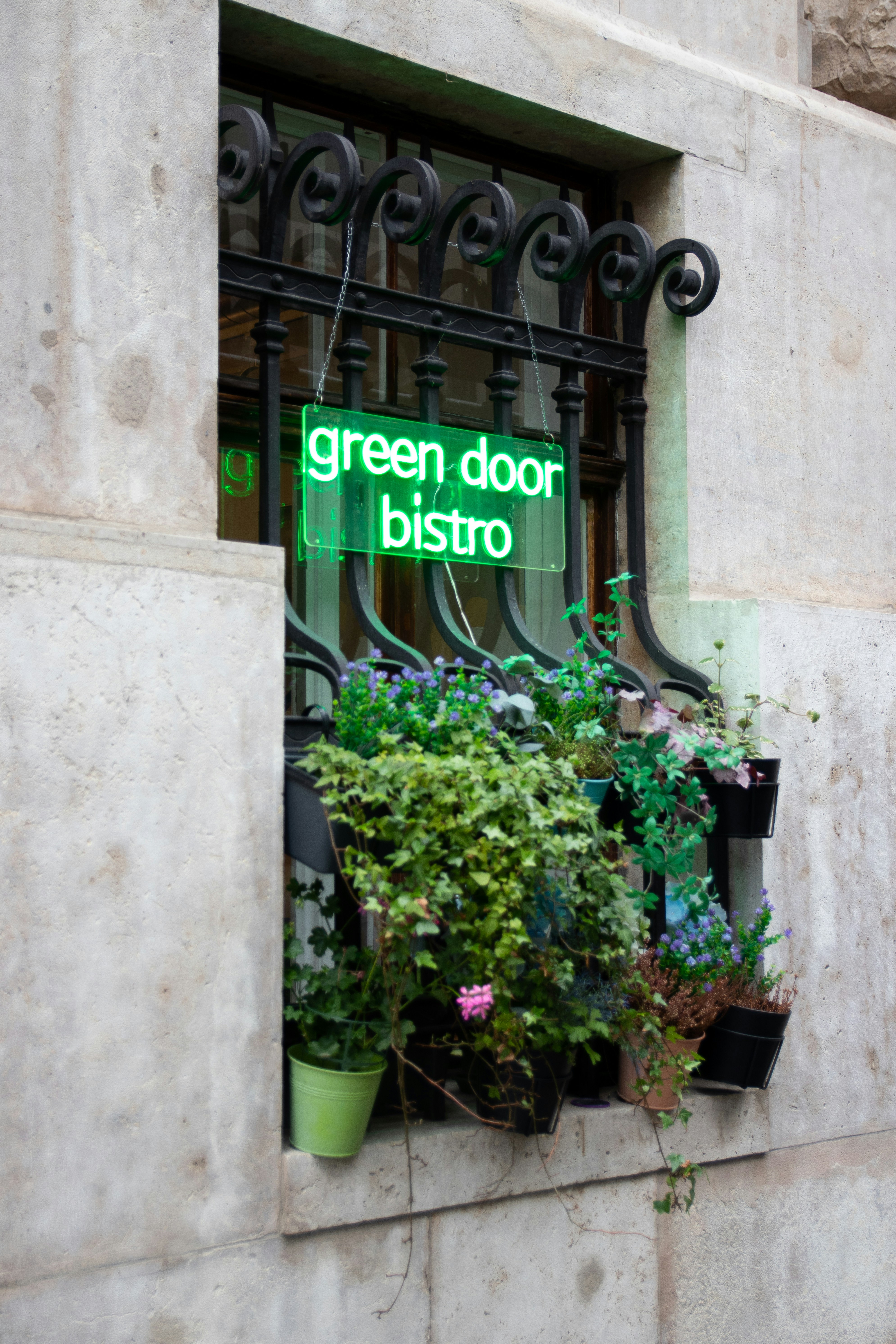 Neon Green Bistro Sign Framed by a Window Garden