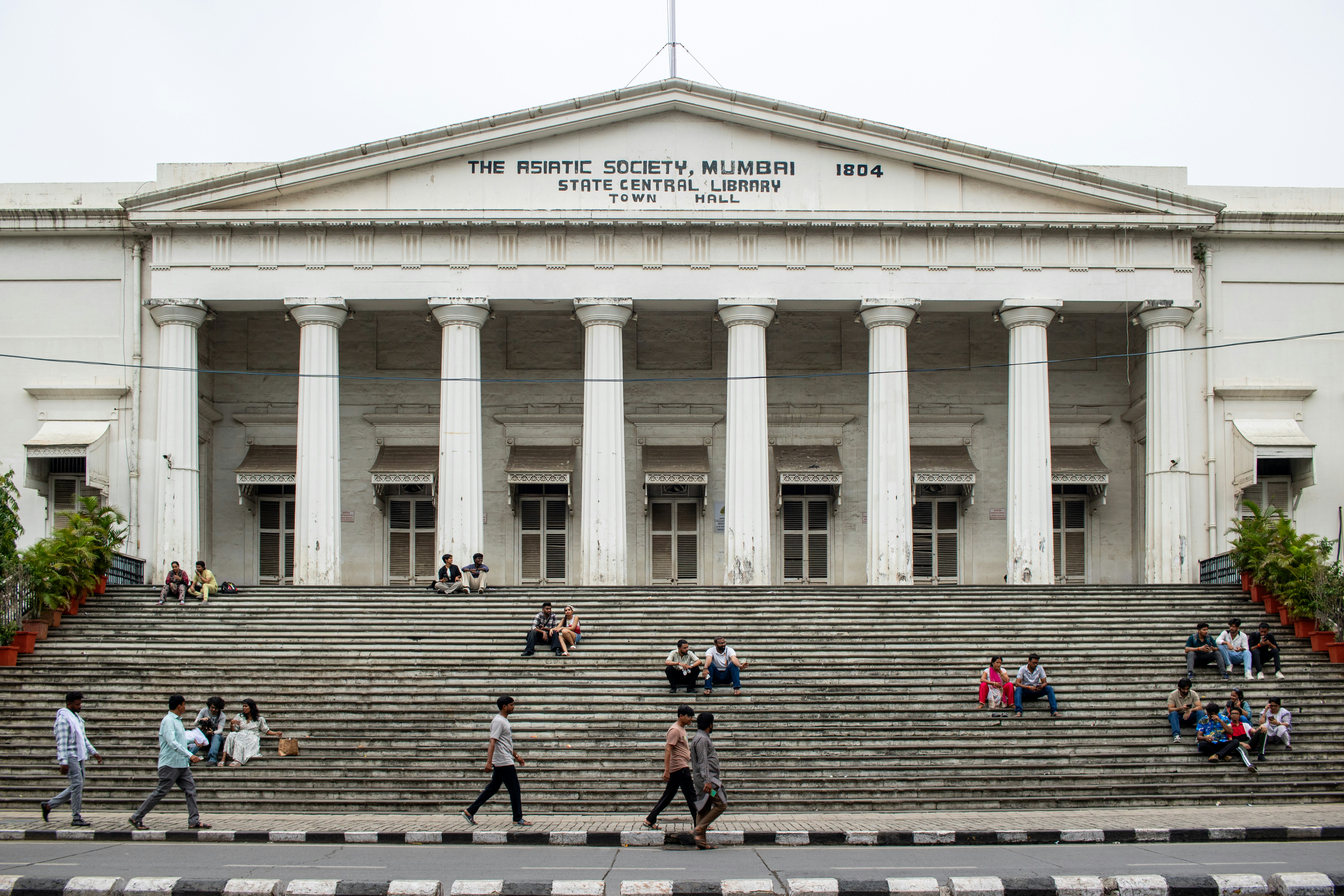 People walk and sit on the steps of a building. photo – Free Building ...