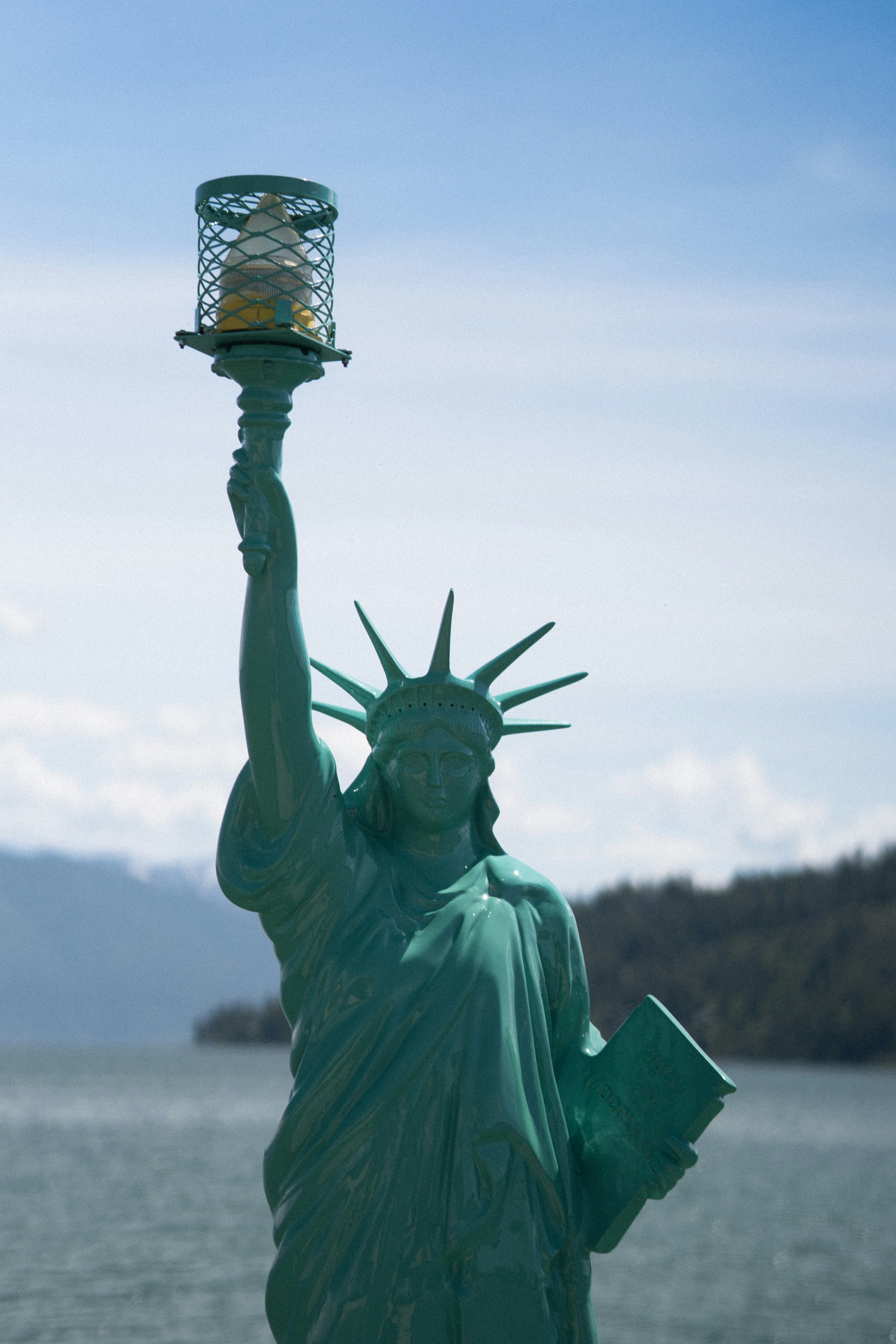 Verdant Liberty by the Bay: Torch Raised Over Quiet Waters