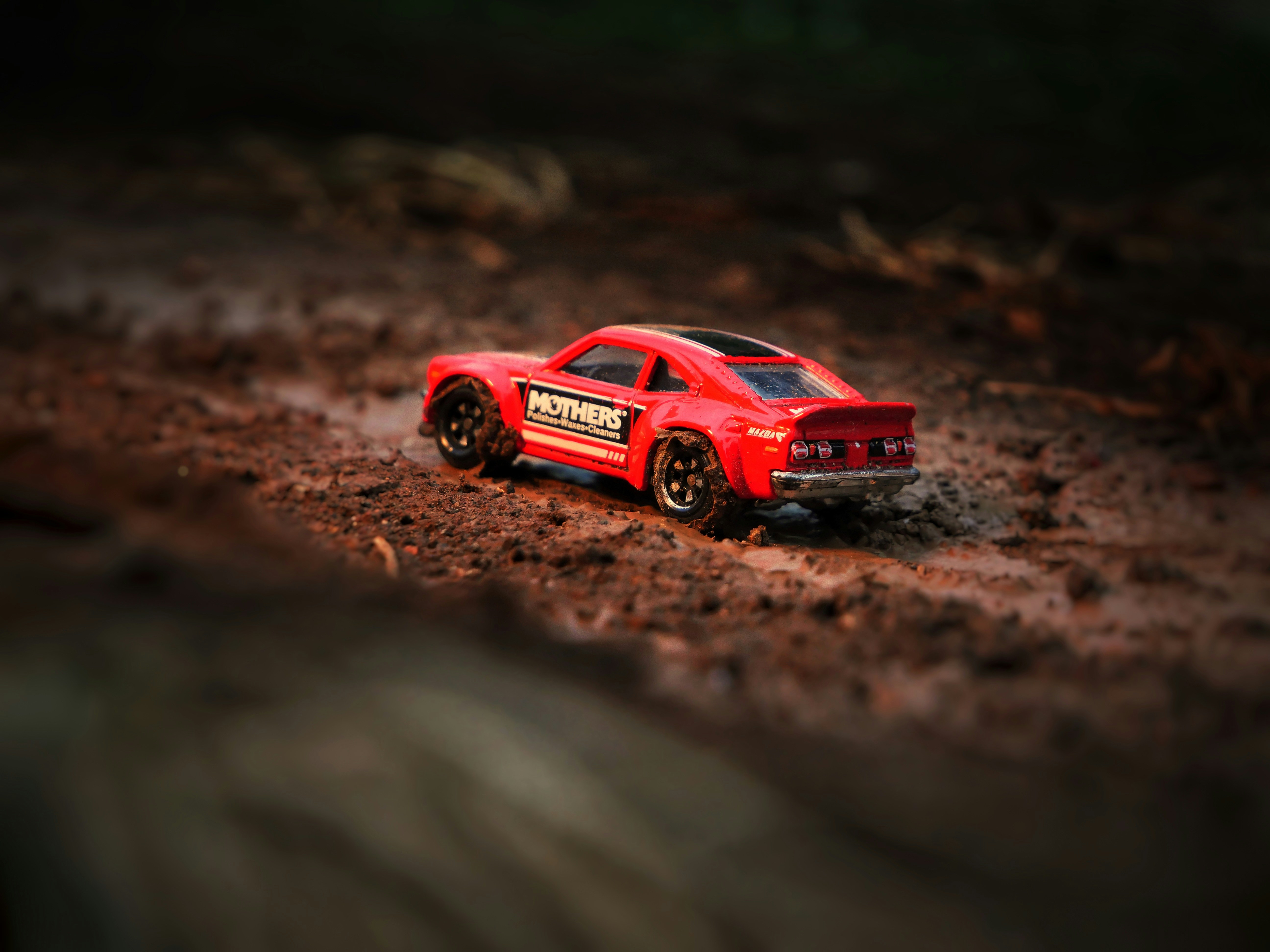 Red RC Car on a Muddy Micro-Track Beneath Forest Dappled Light