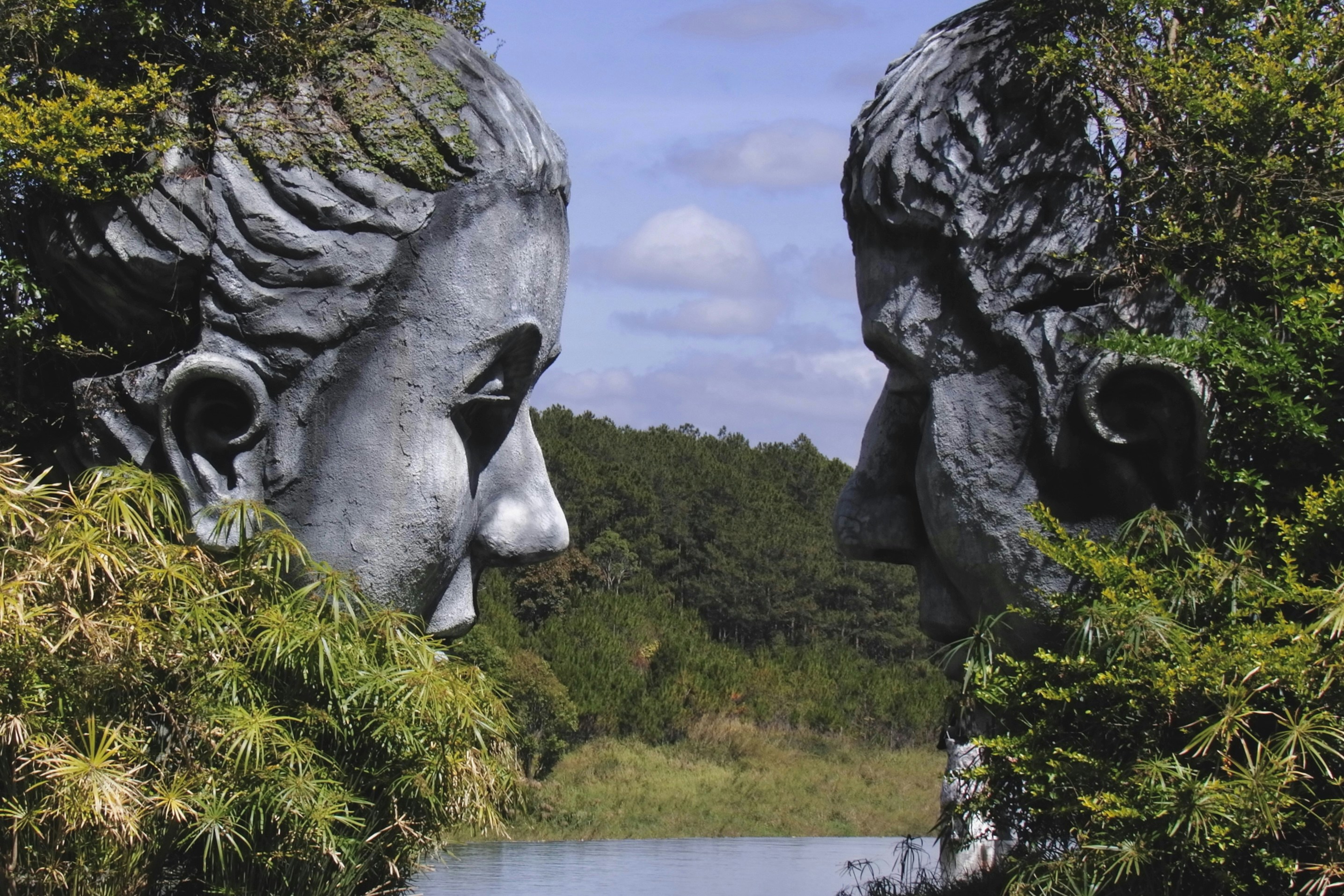 Two stone faces emerge from greenery. photo – Free Forest Image on Unsplash