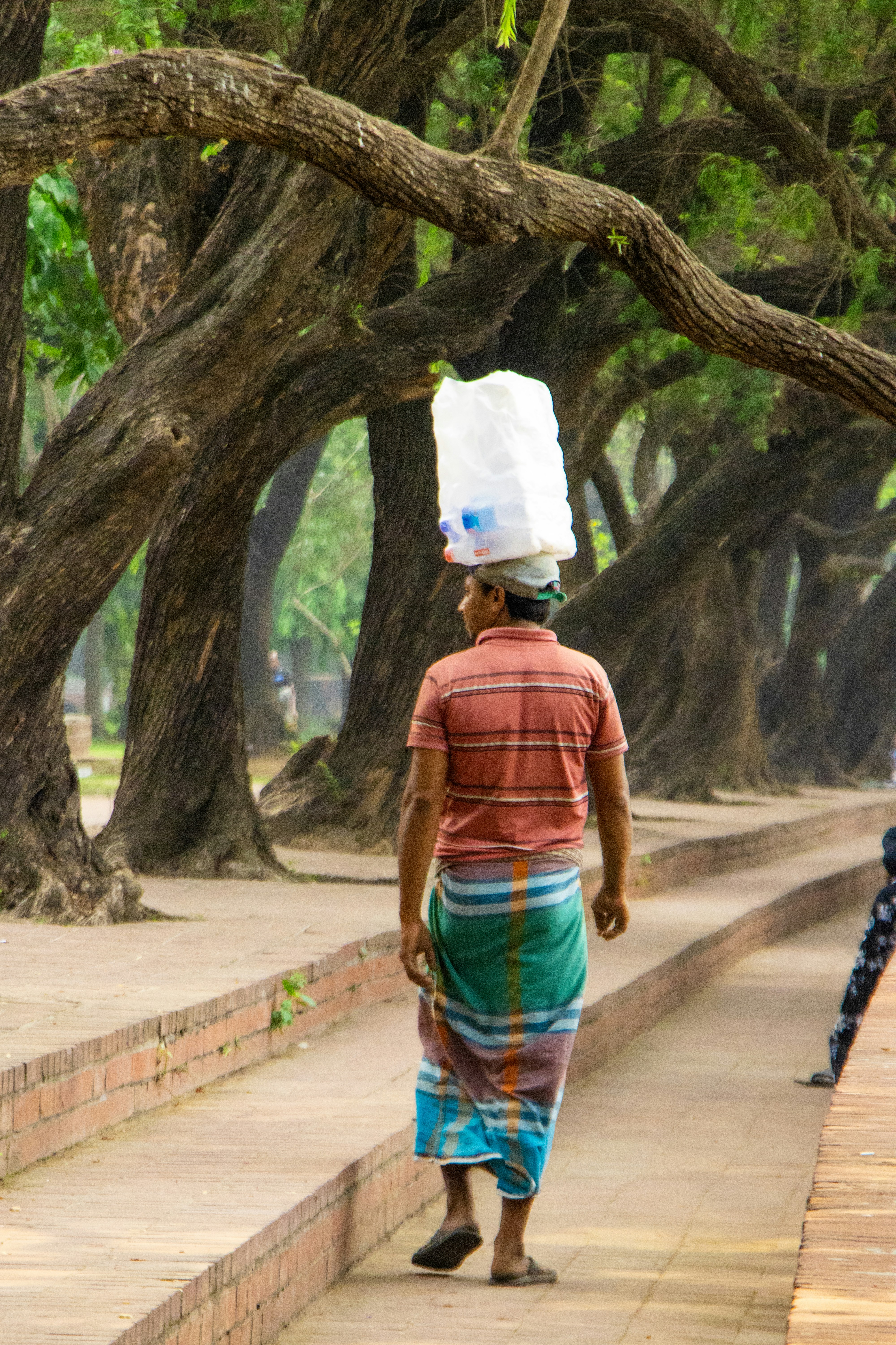 A man balances a container on his head.