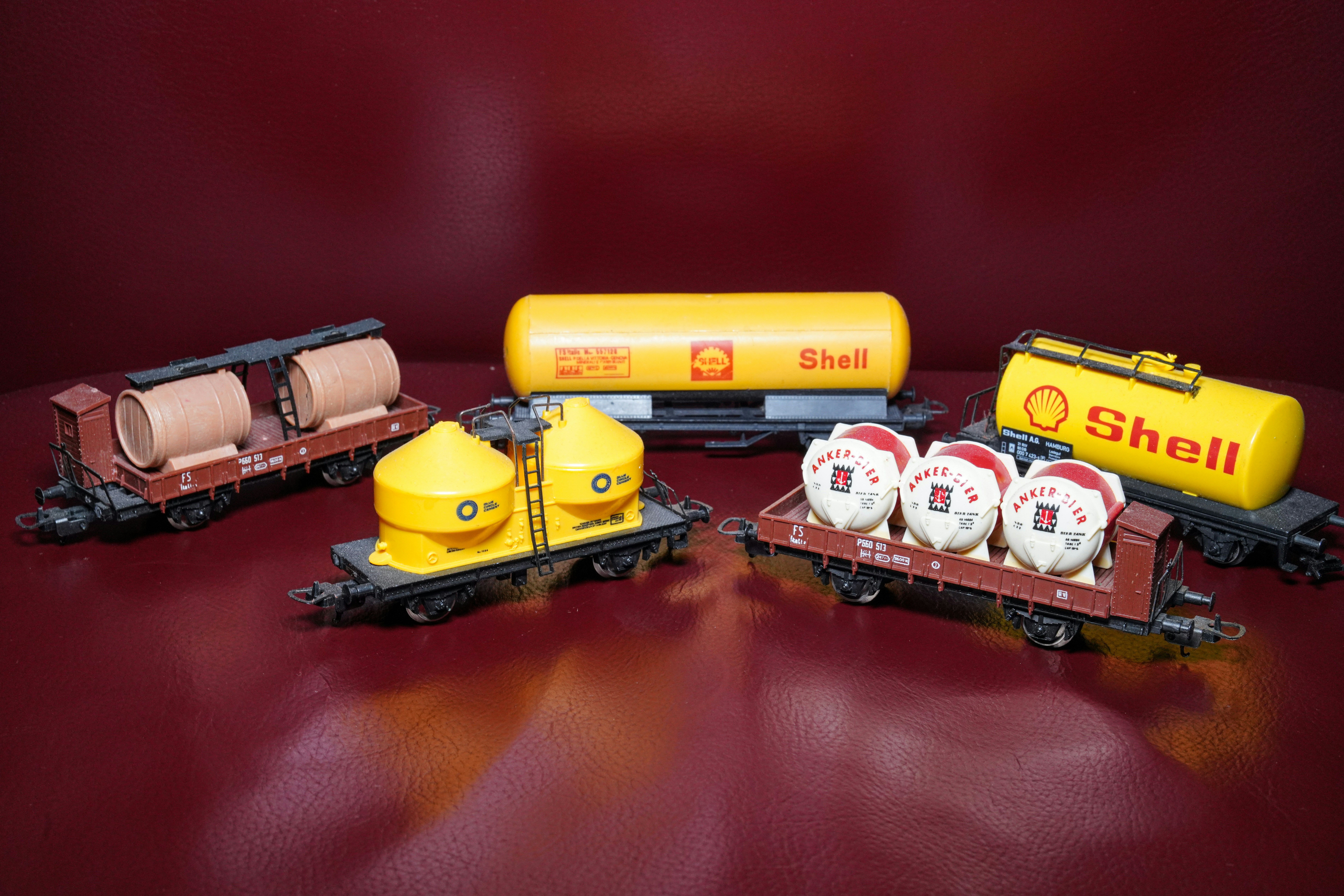 Crimson Stage: Tiny Shell Tank Cars on a Velvet Red Surface