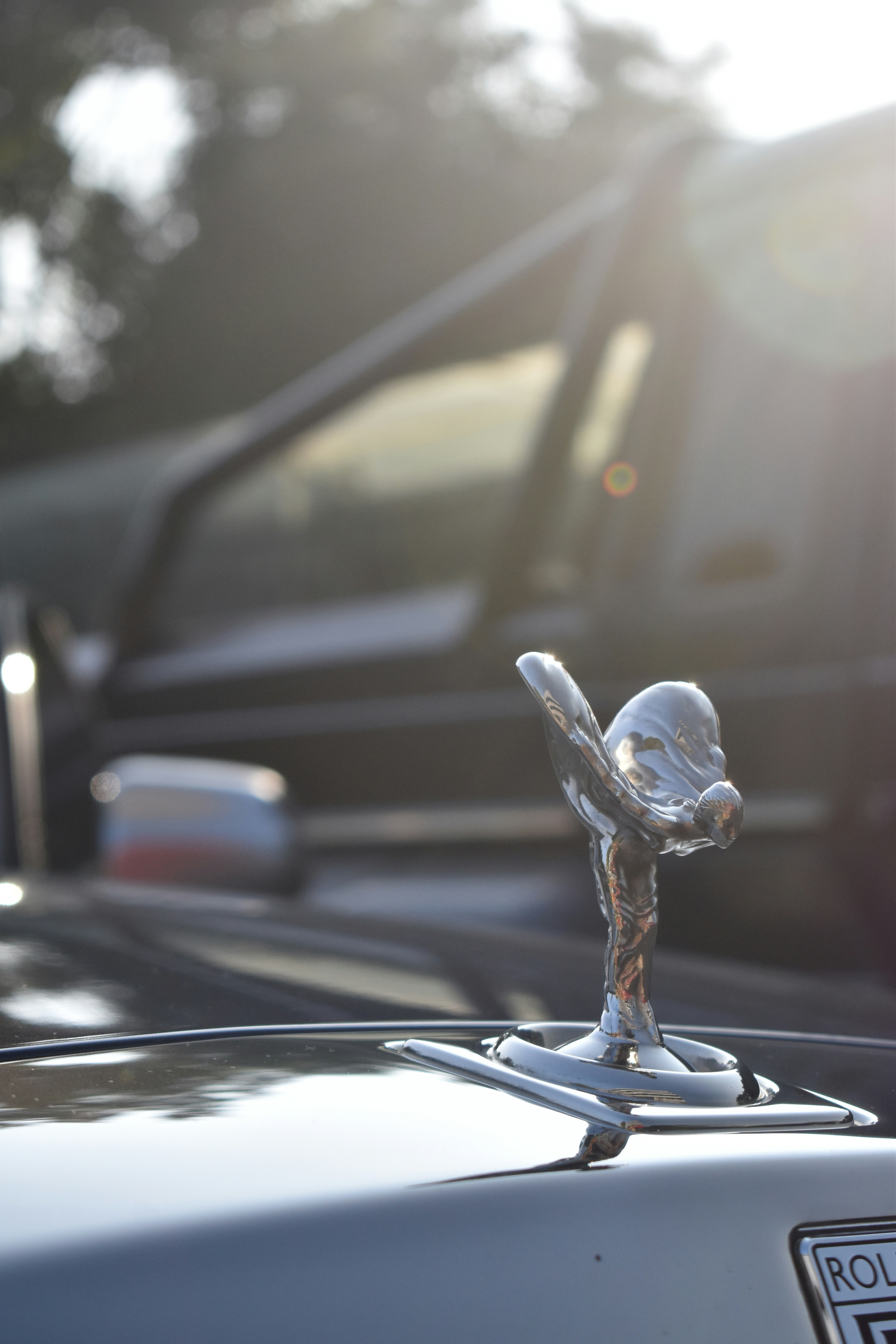 A rolls royce hood ornament glints in sunlight.