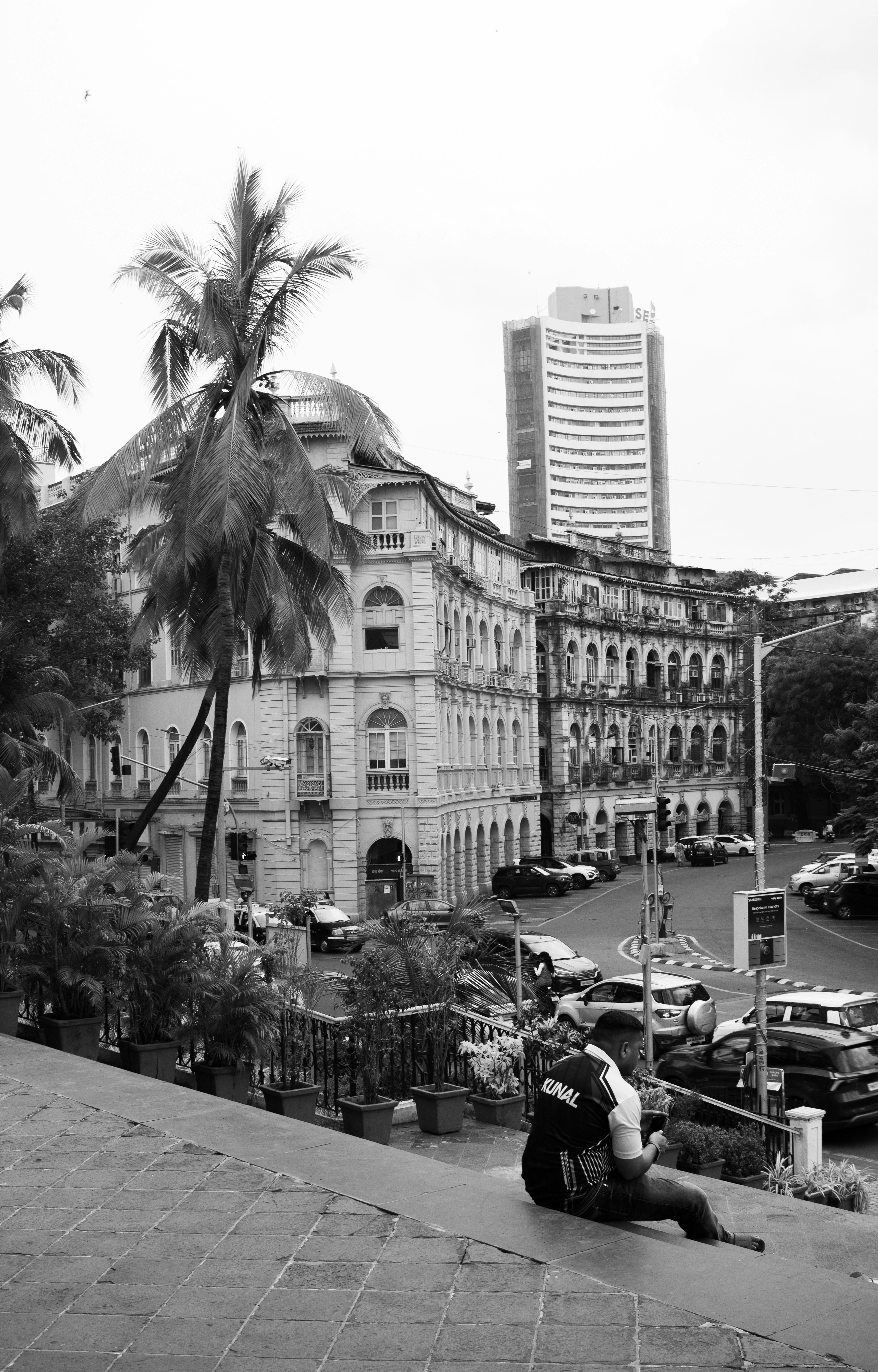 Paused on the Terrace: a grayscale cityscape of arches, palms, and a lone observer