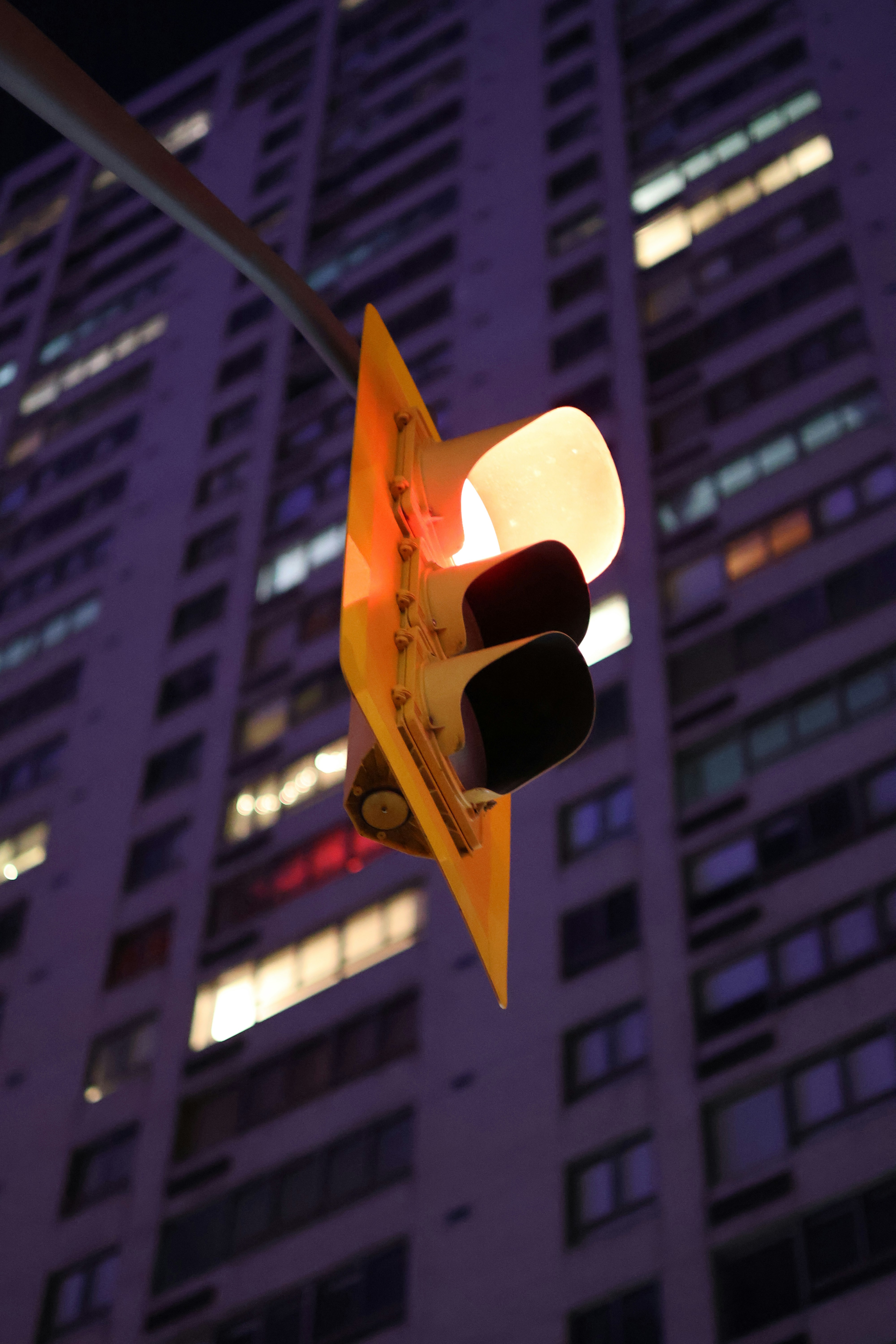 Tilted Traffic Signal, Night City: Warm Glow Against a Glassy Skyline