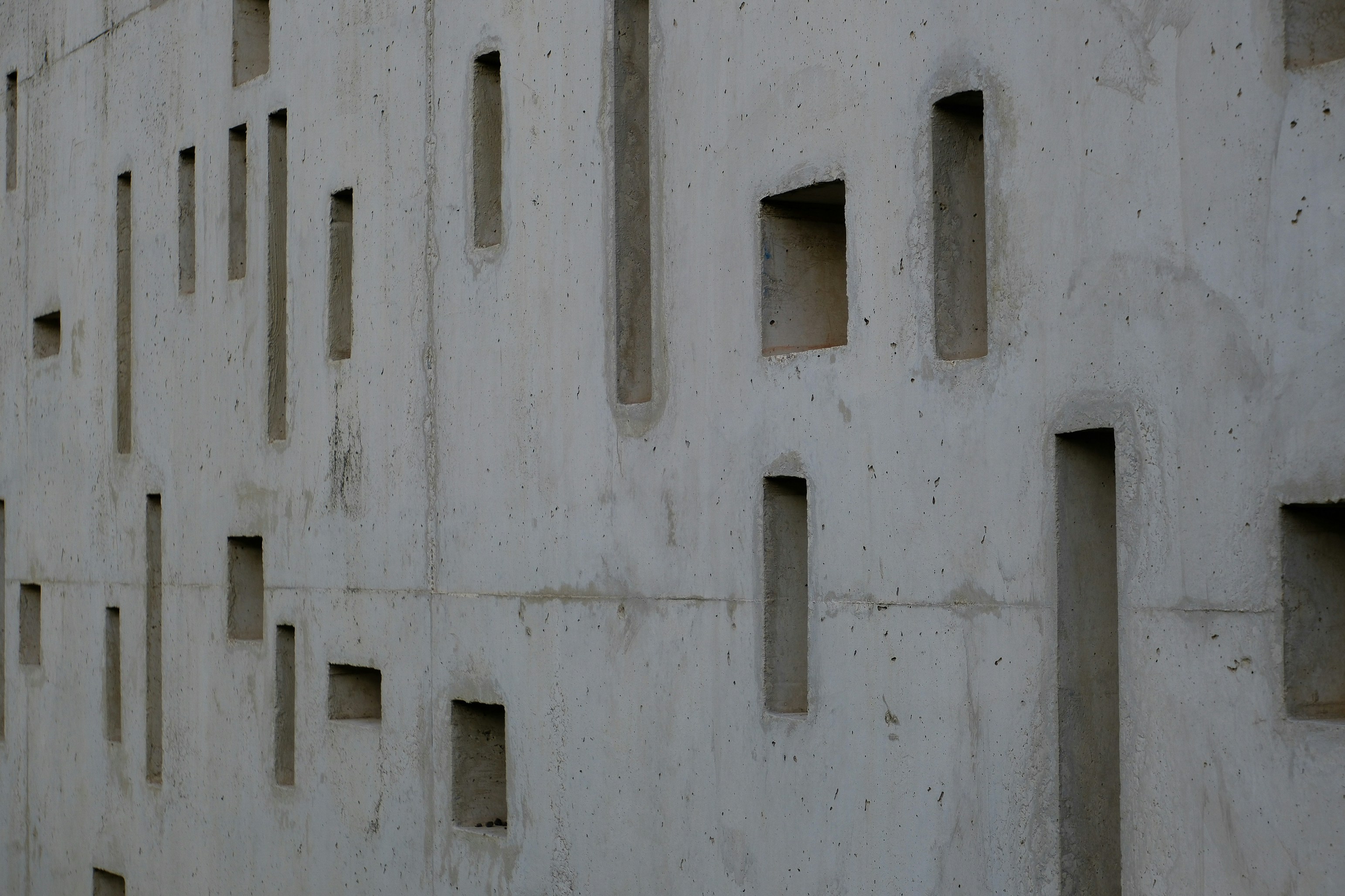 A concrete wall features rectangular openings.
