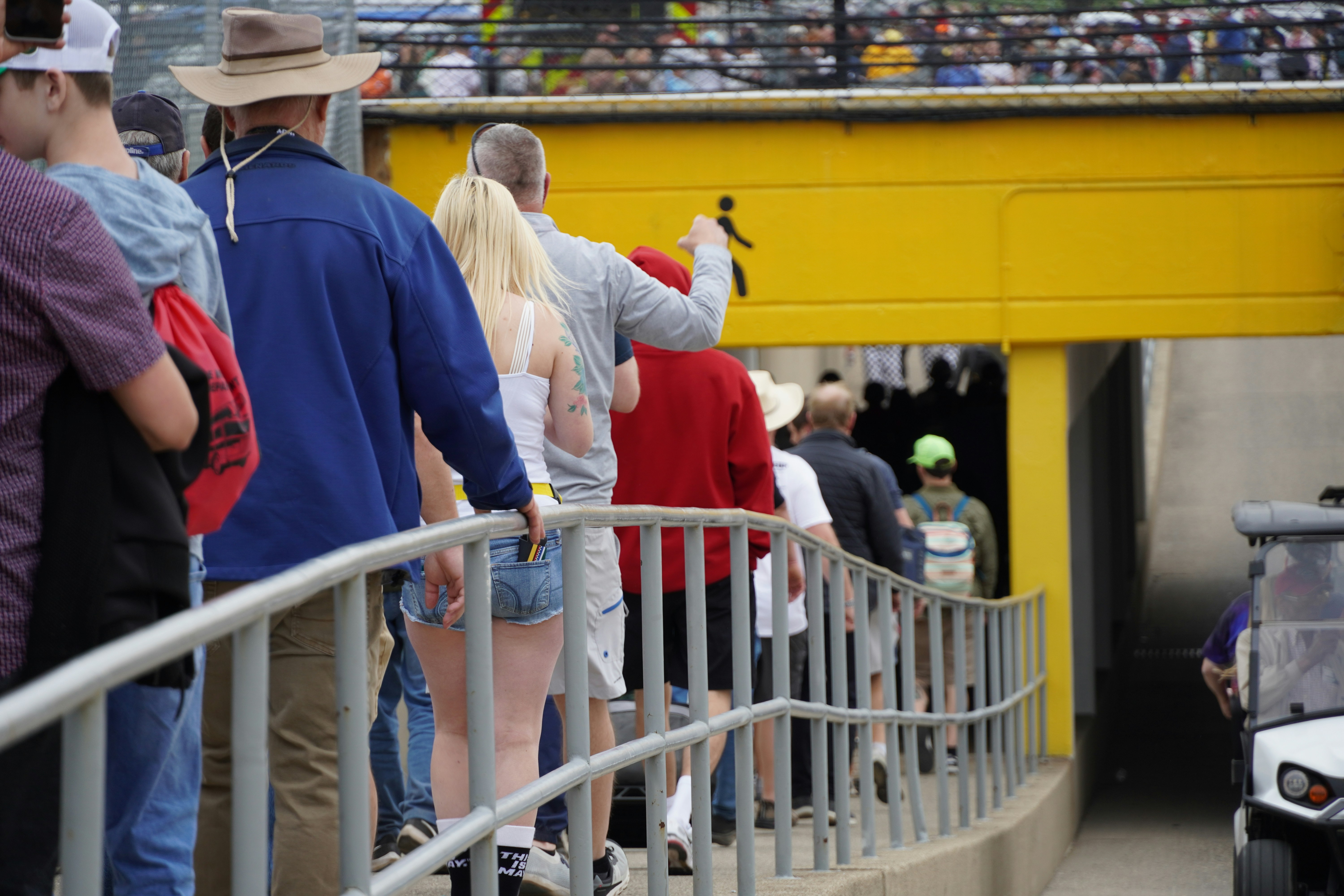 People line up by a railing to enter somewhere. photo – Free People ...