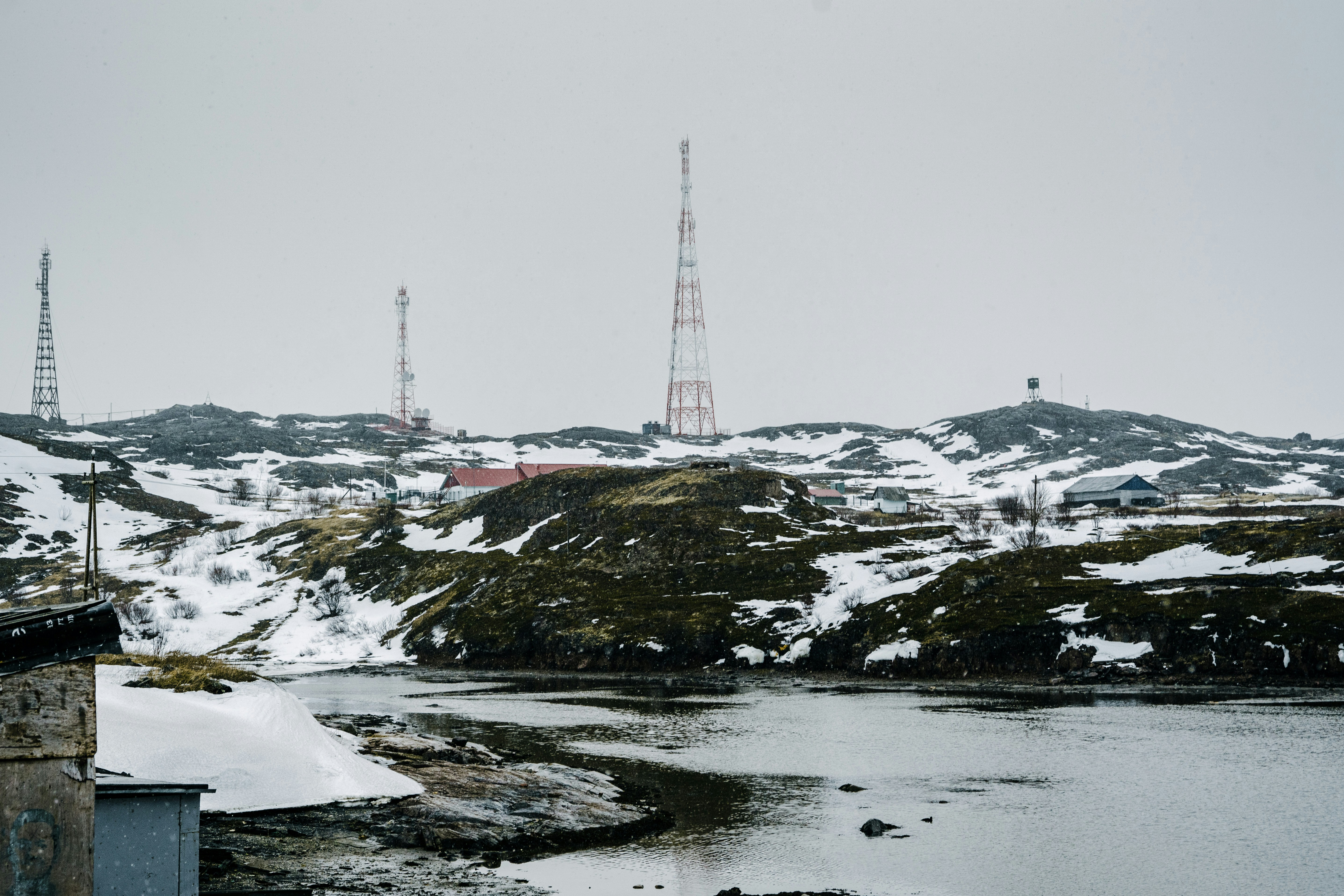 Snowbound Ridge of Signals: Towers Crown a Quiet Arctic Shore