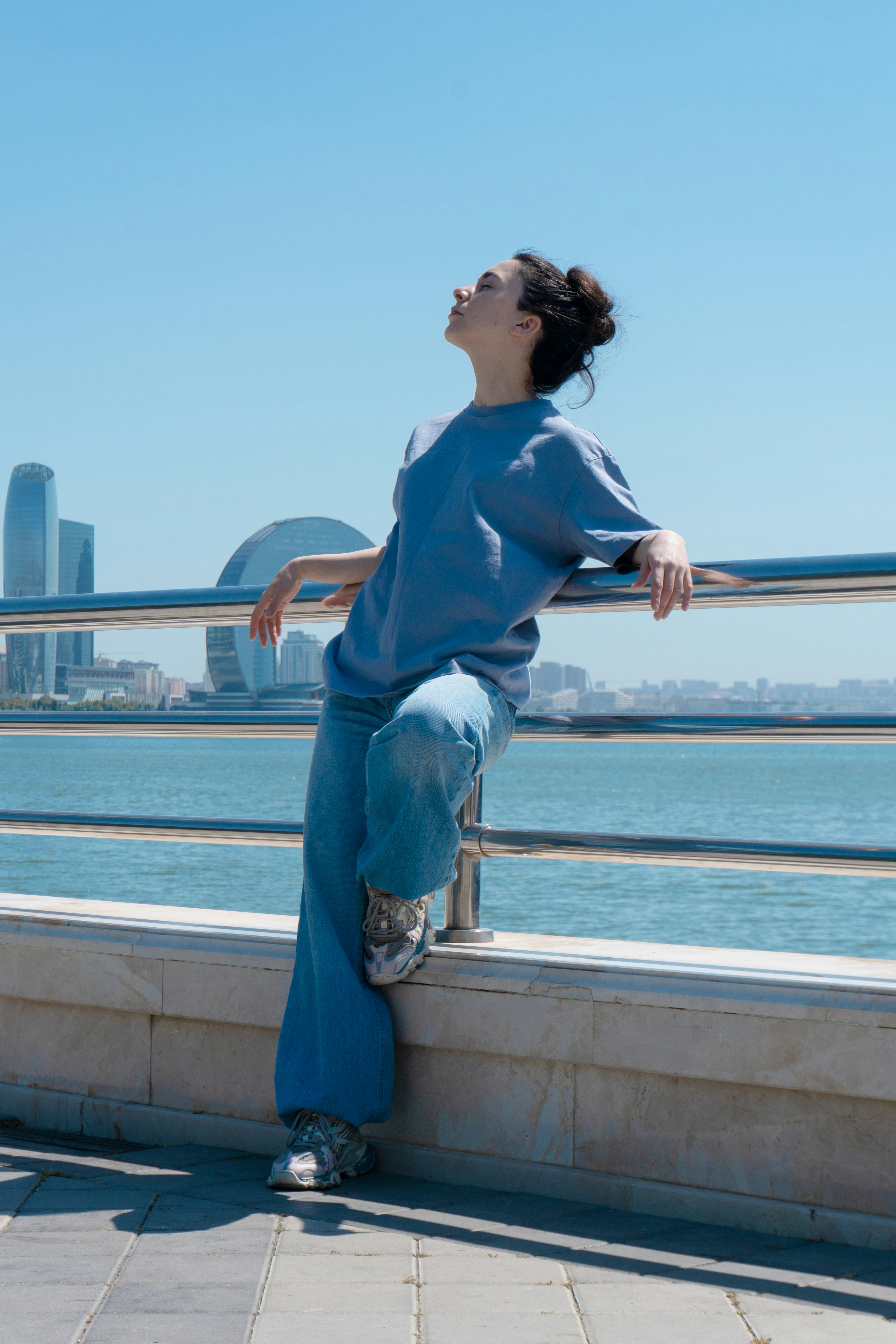 Relaxed on the Waterfront: A Quiet Pose with Cityscape Backdrop