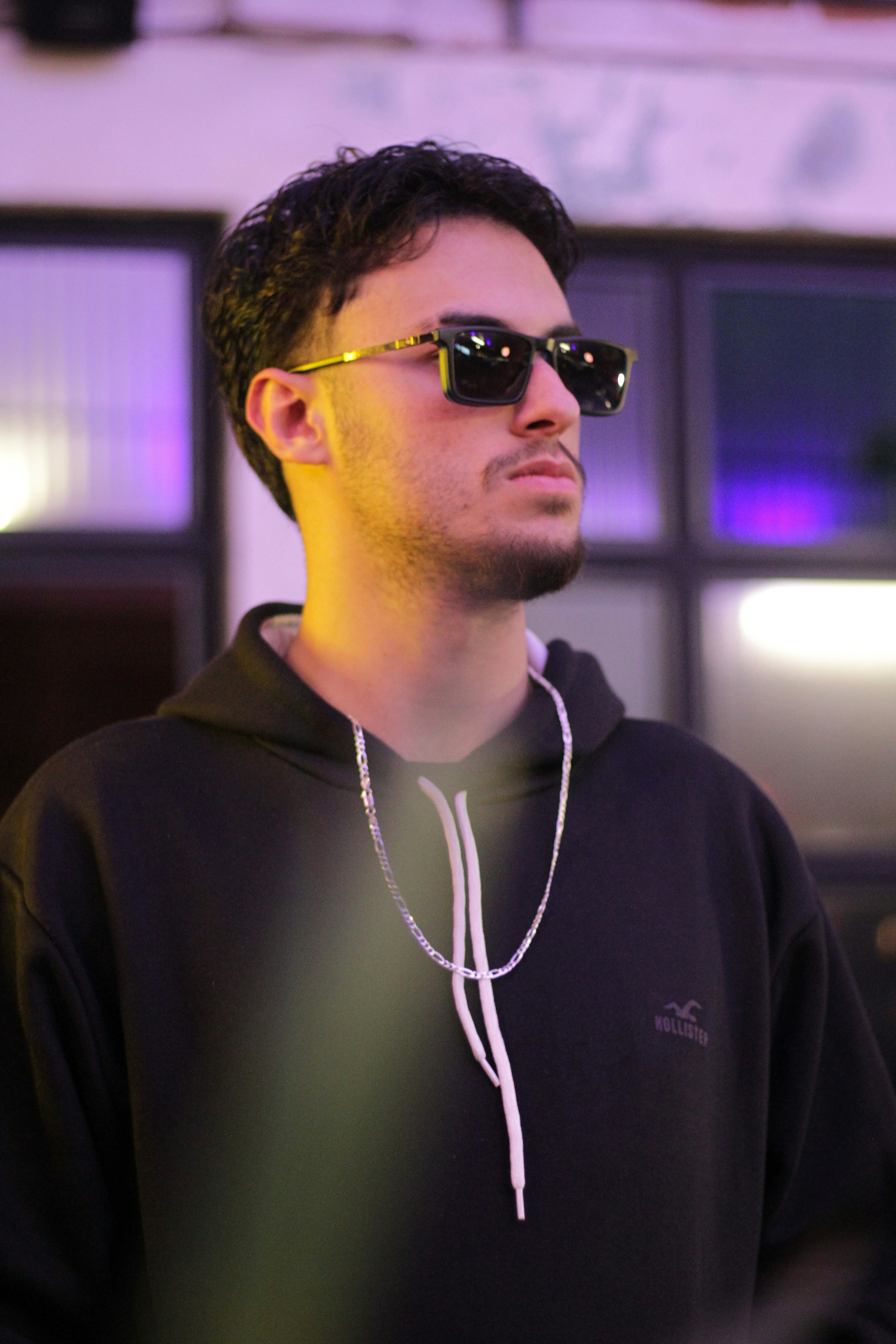 A young man is wearing sunglasses and a hoodie.