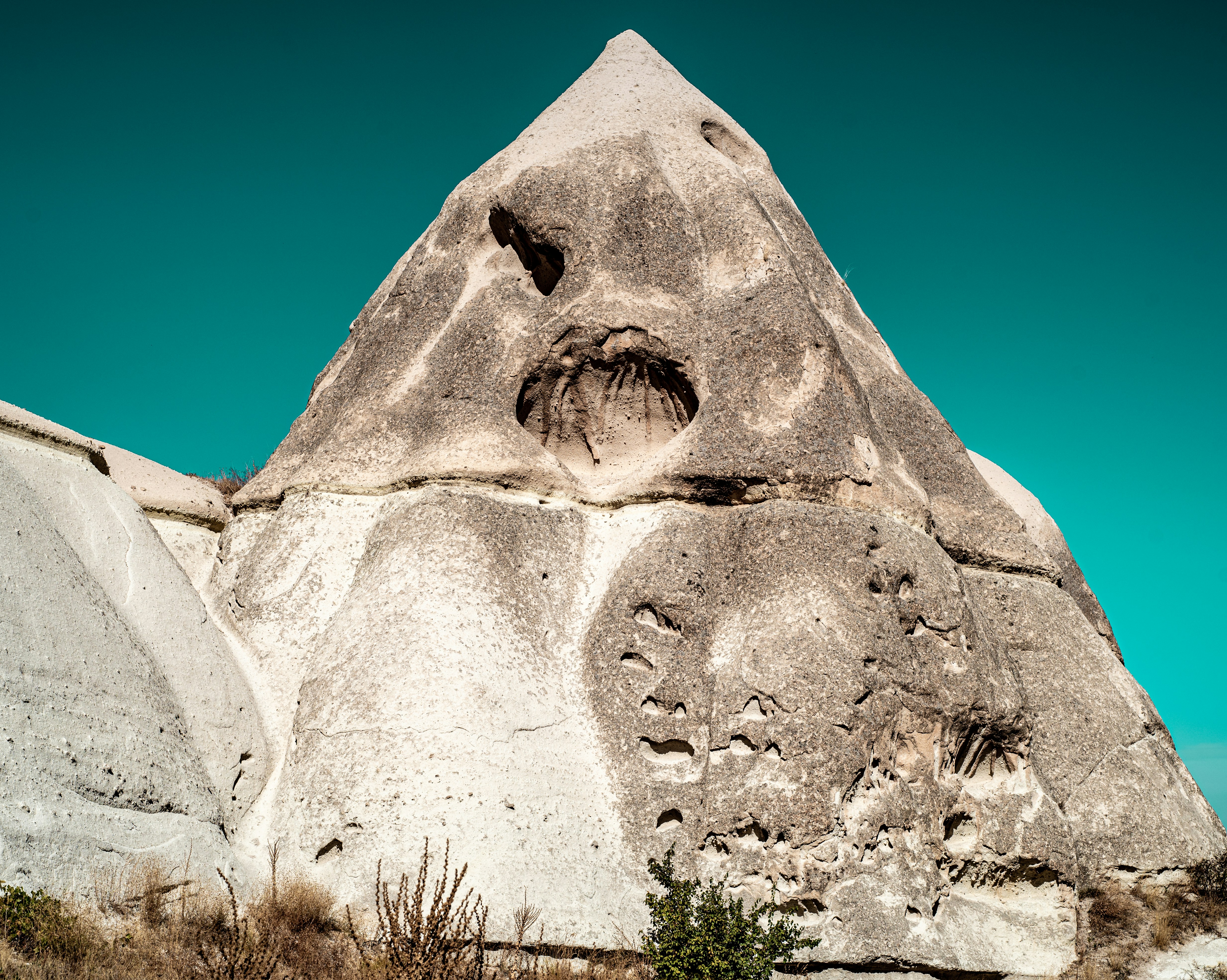 A unique rock formation stands against a teal sky.