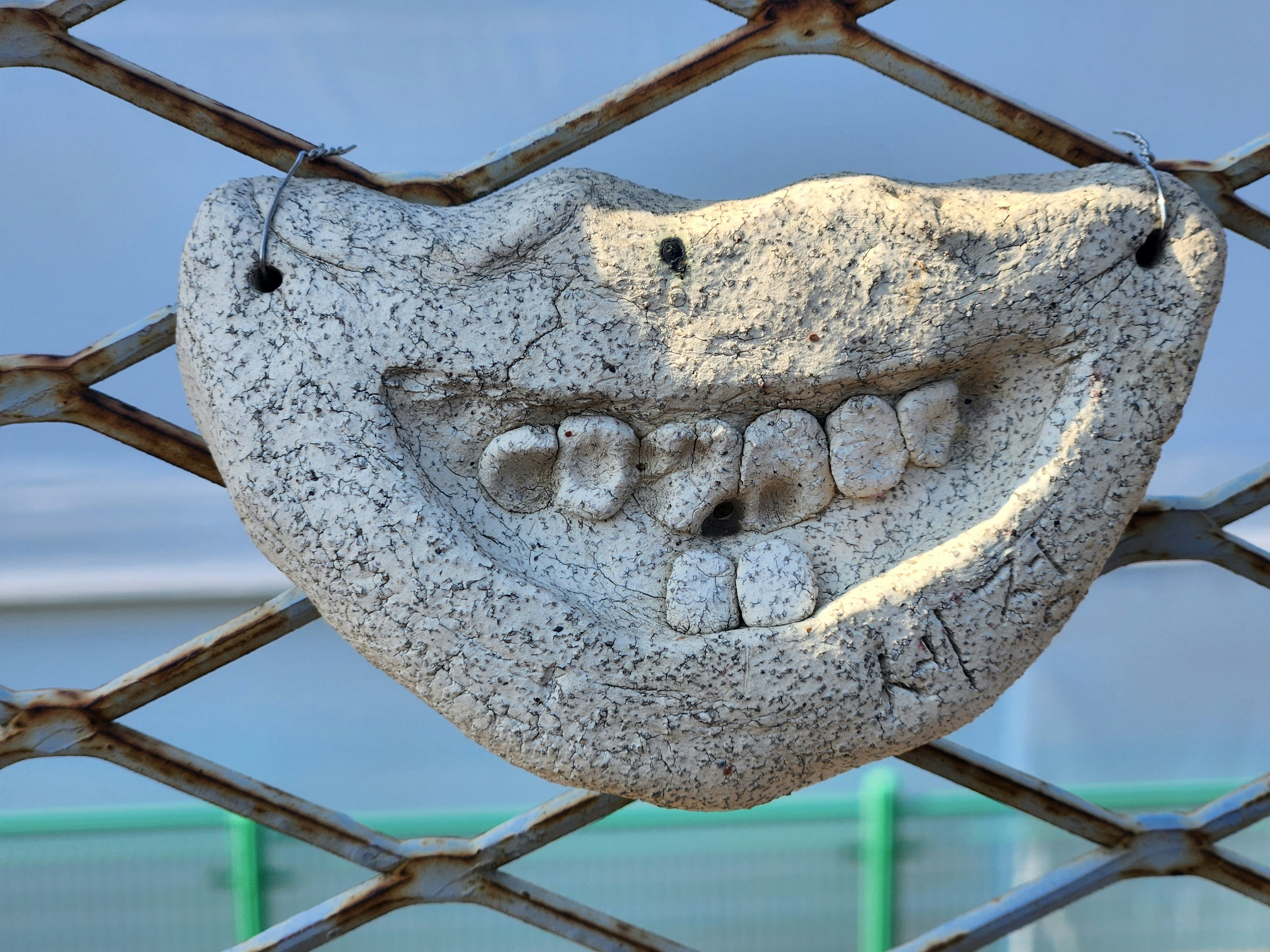A smiling stone face hangs on a metal grate. photo – Free Seoul Image ...