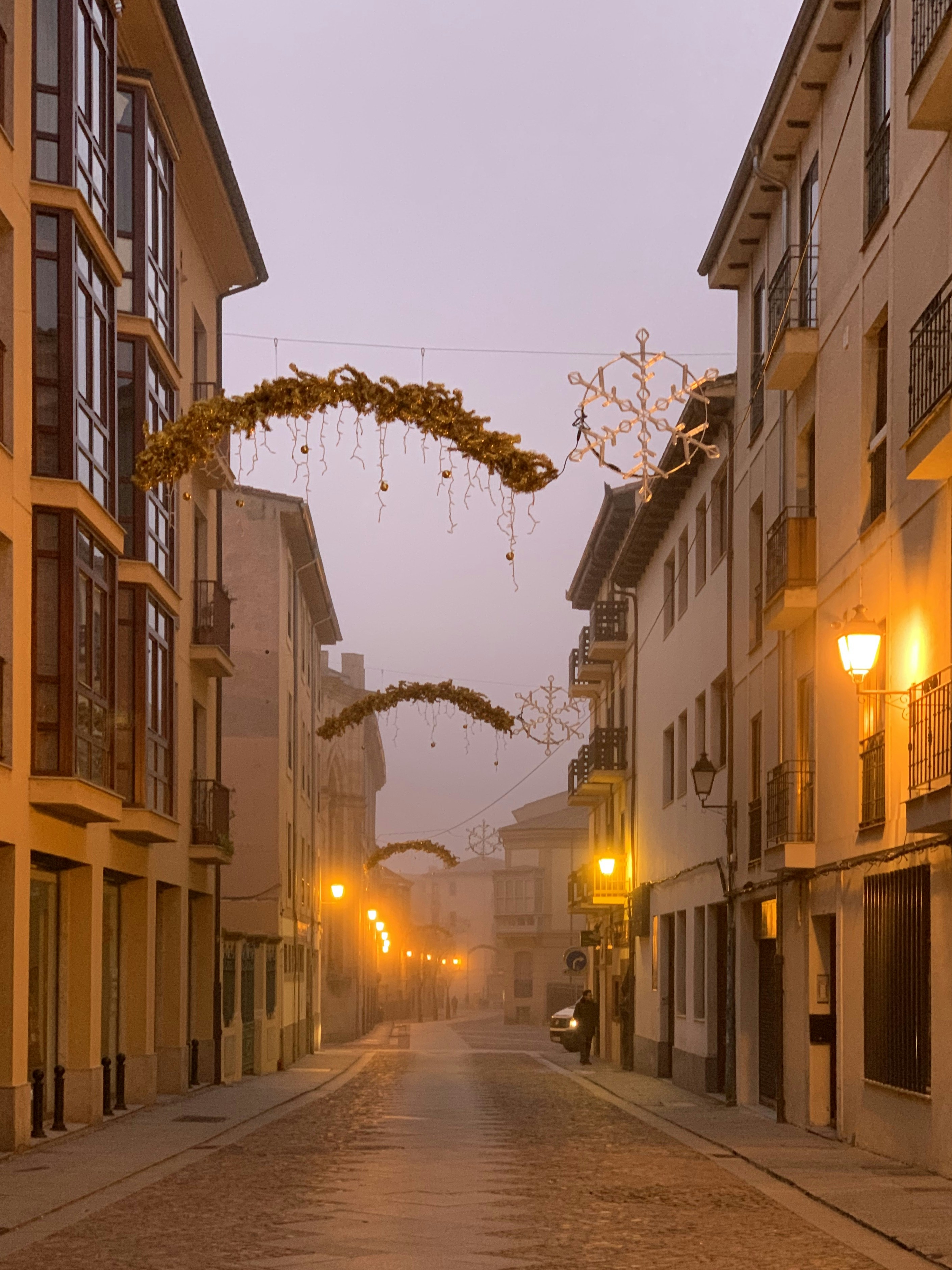 Vanishing Glow: Lantern-Lit Cobblestone Street in Fog