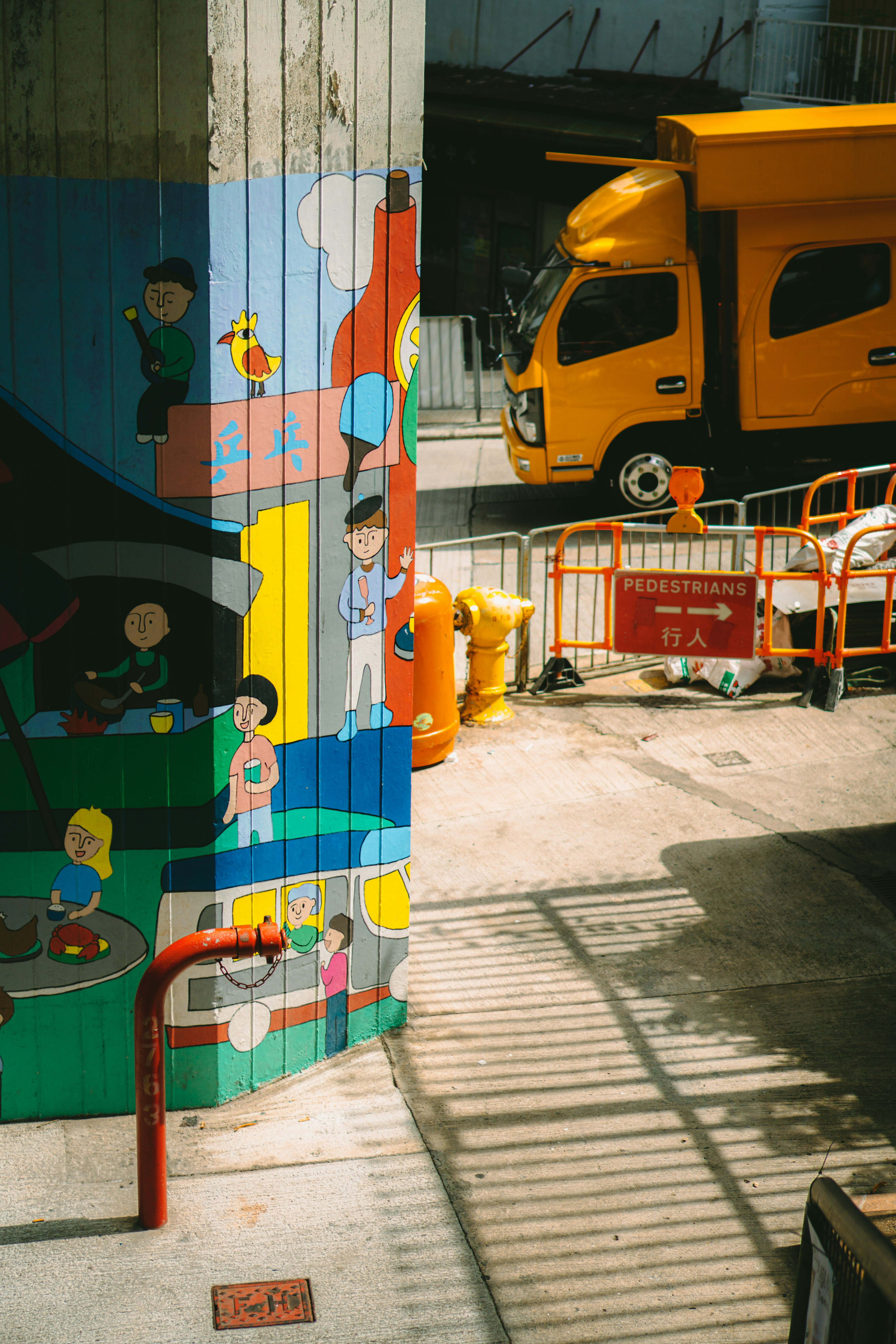Murals and Machinery at Noon: A Sunlit Urban Corner