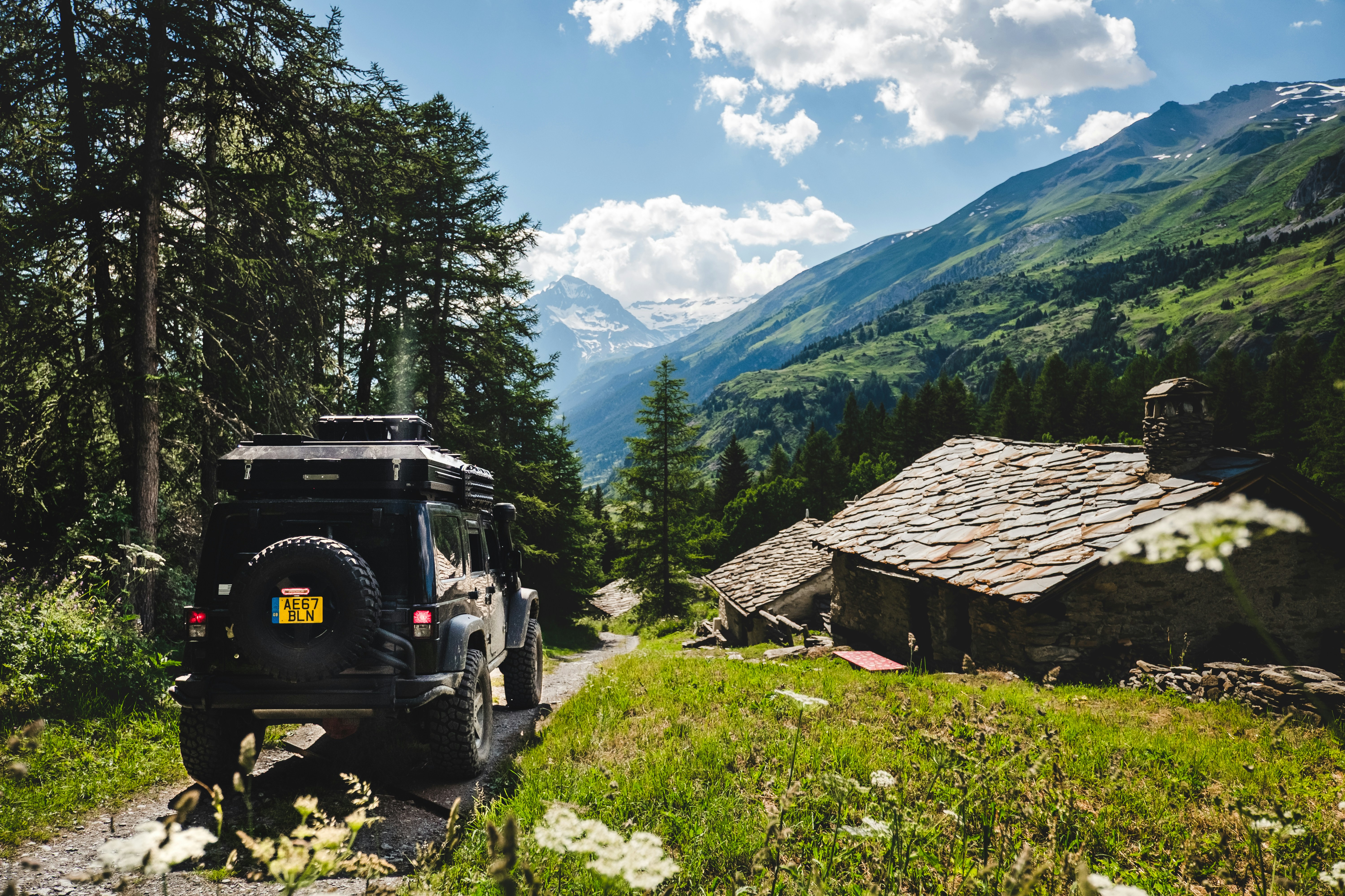 Rugged Arrival: Off-road Quiet by a Stone Chalet Under Alpine Peaks