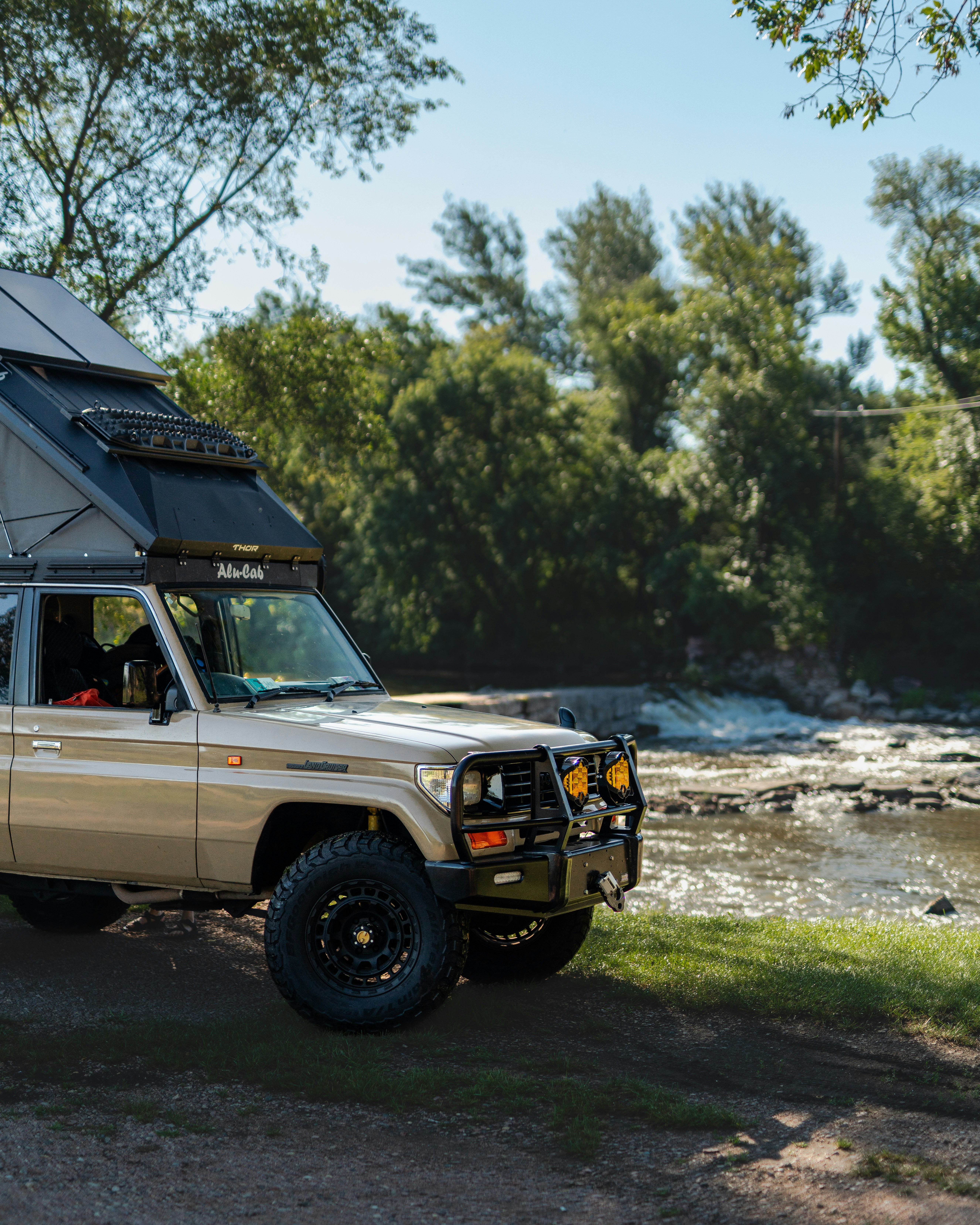 Sunlit Overland by the River: A vintage camper ready for the next trail.