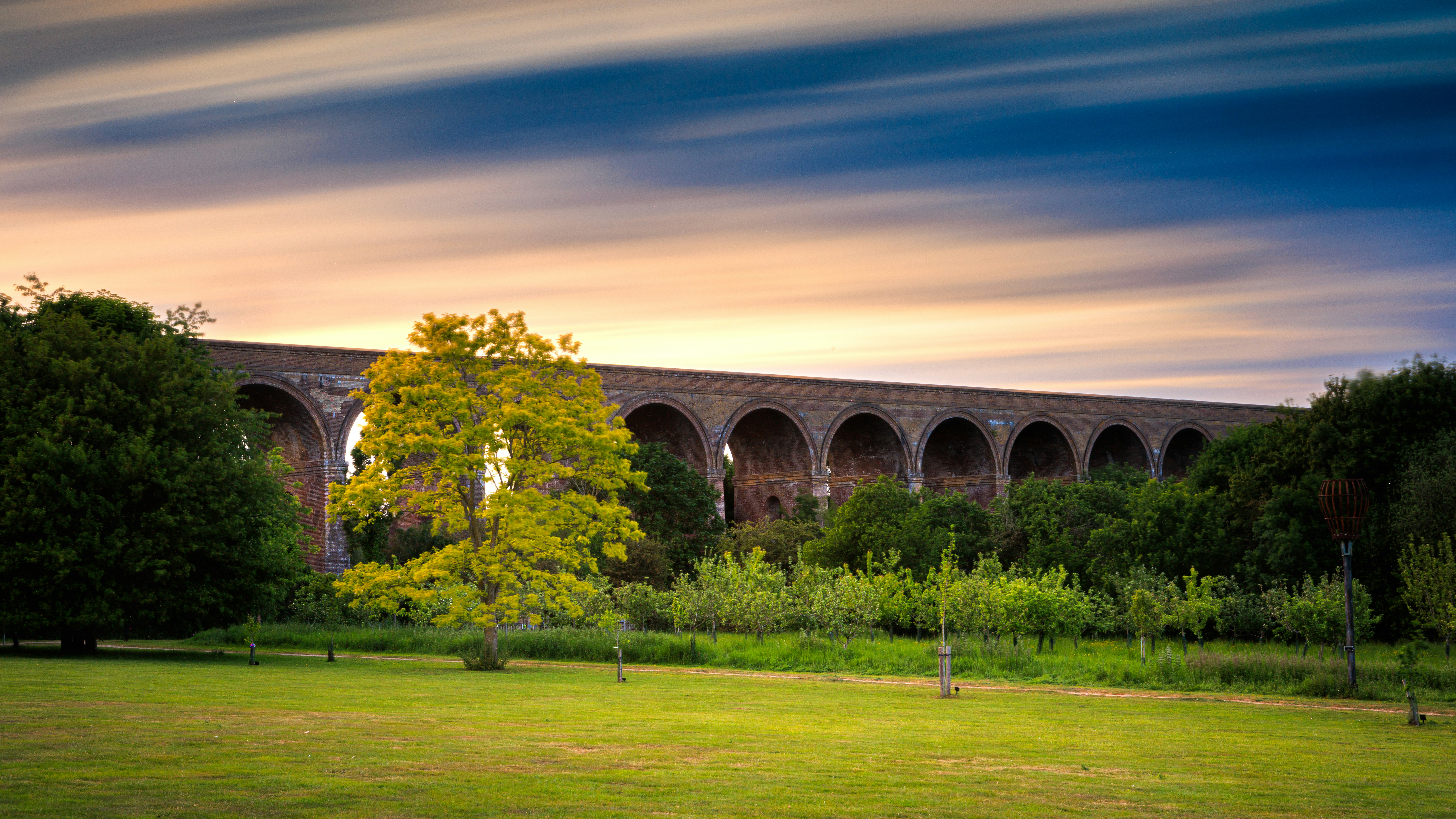 Arched Viaduct Framed by a Golden Tree under a Blurred Sunset