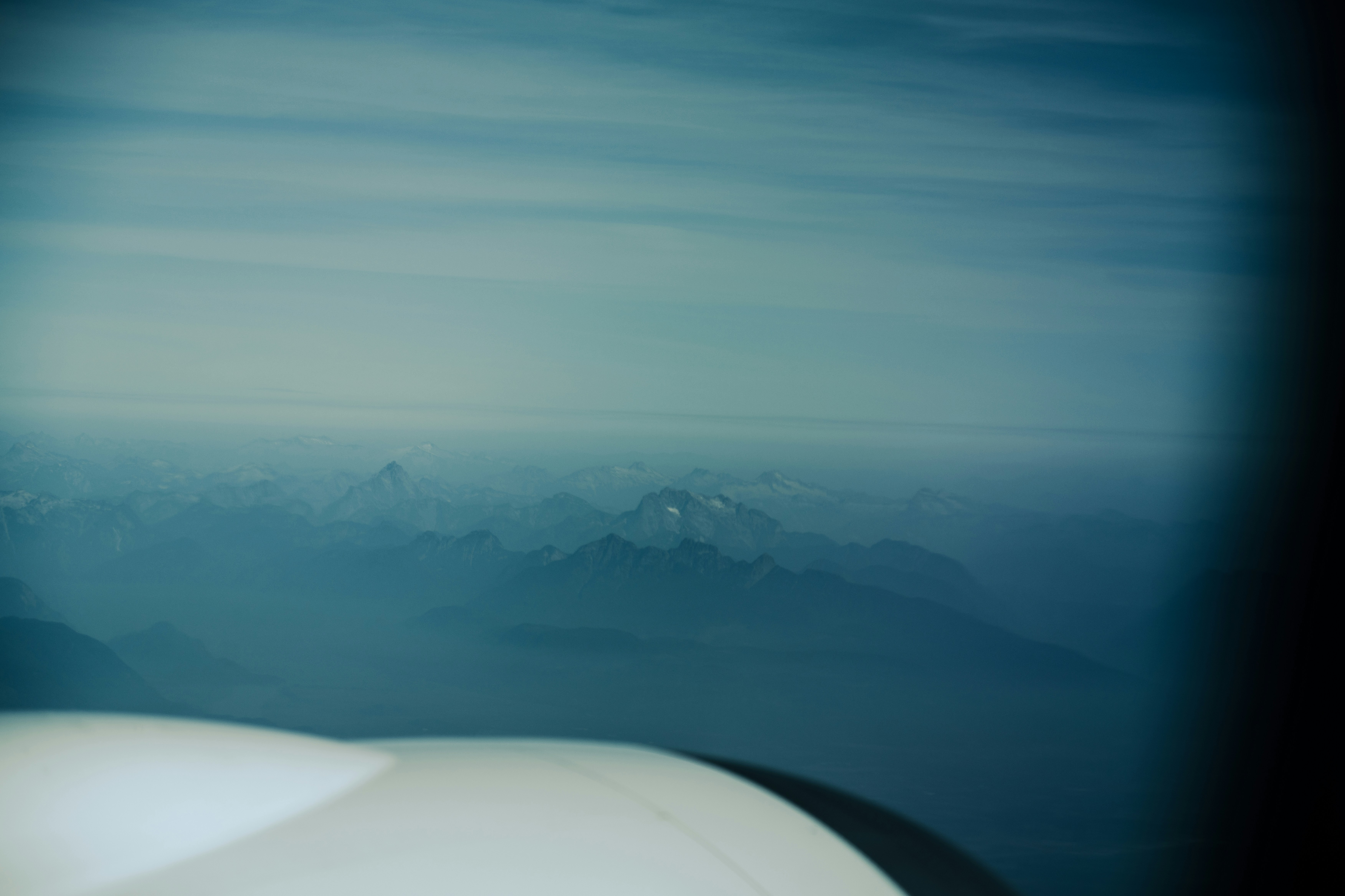 Azure Horizon: Snow Peaks Framed by a Wing
