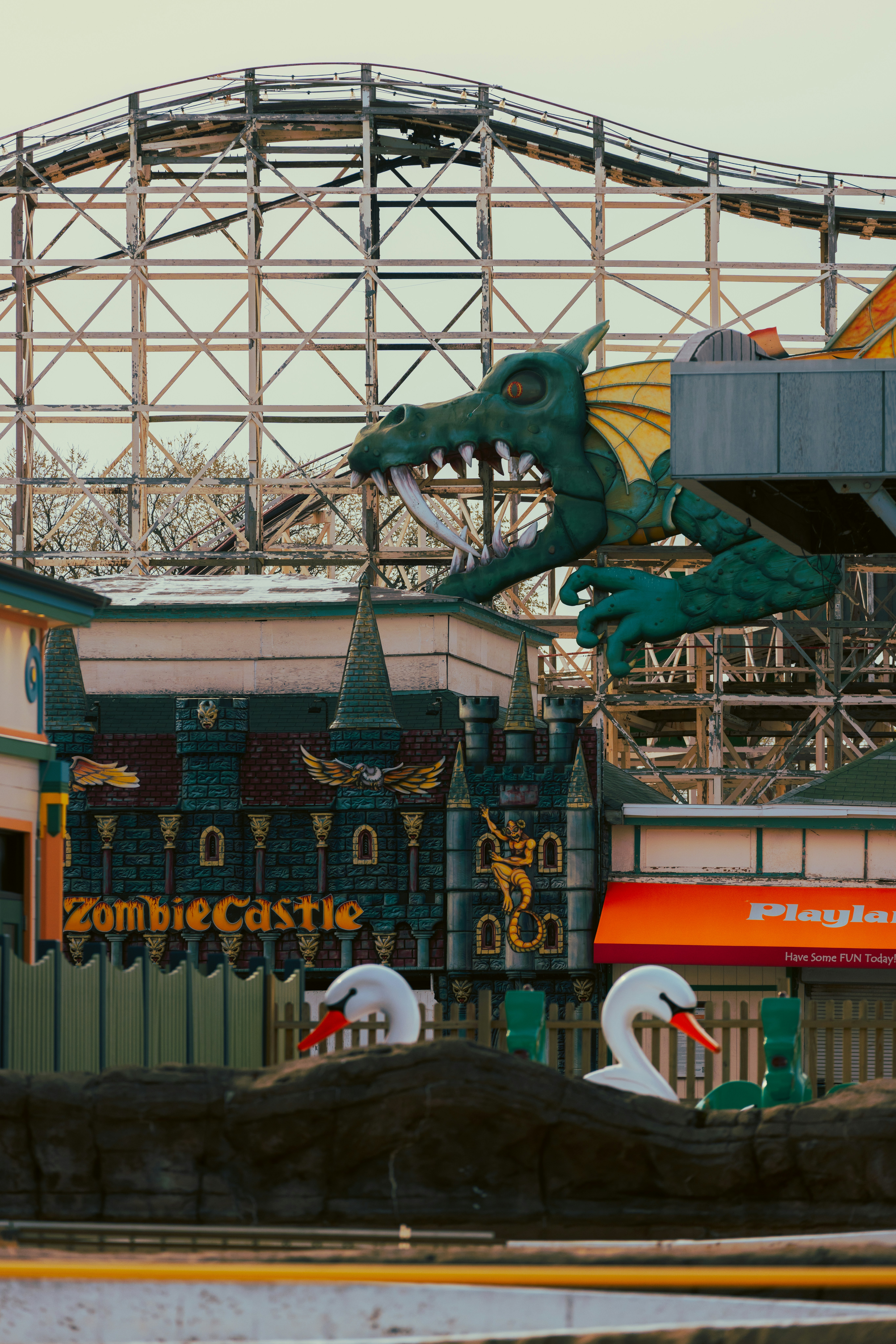 Dragon Over ZombieCastle: A Retro Park's Wooden Coaster and Swan Foreground