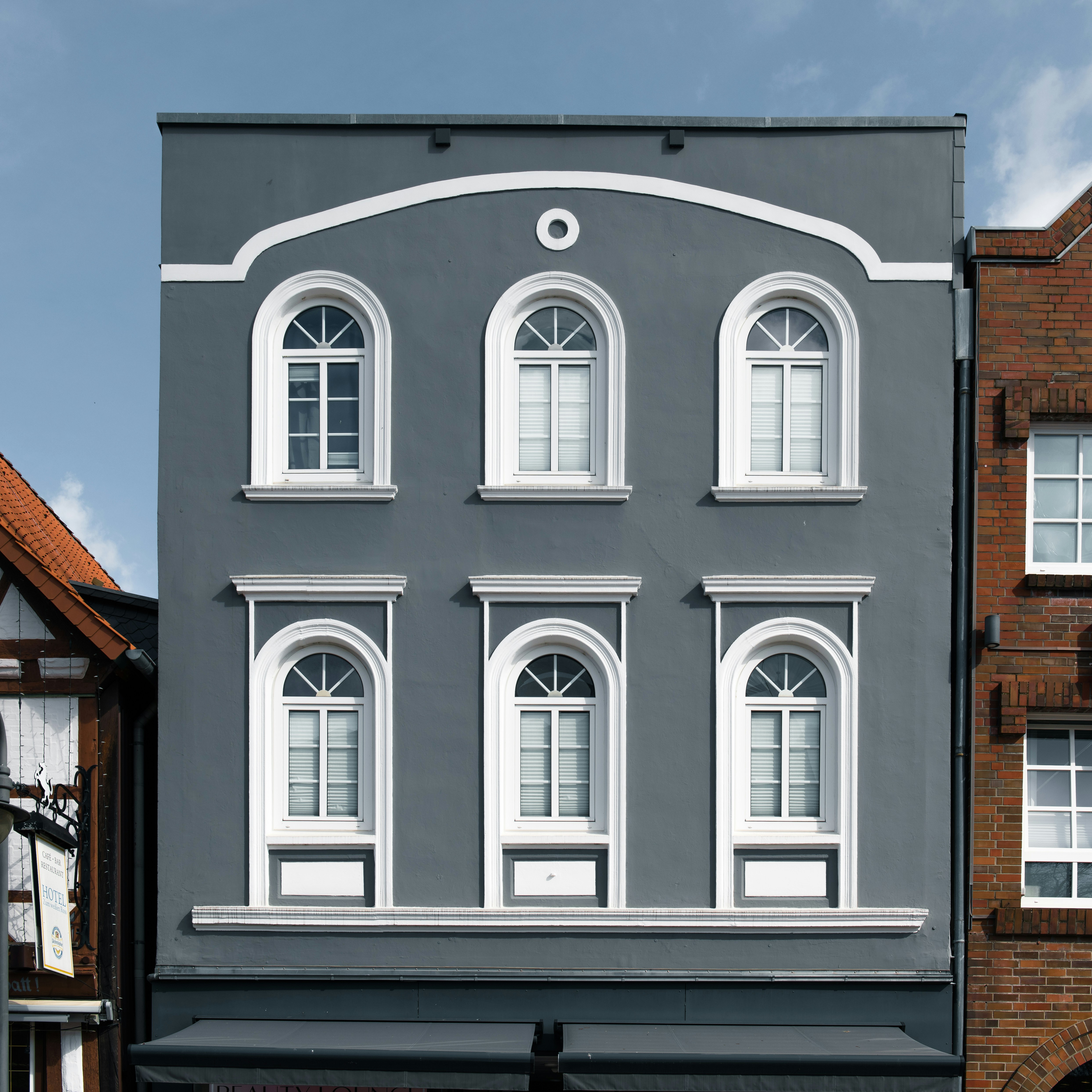 Symmetric Facade: Three Arched Windows and a Worn Yet Elegant Street Sense