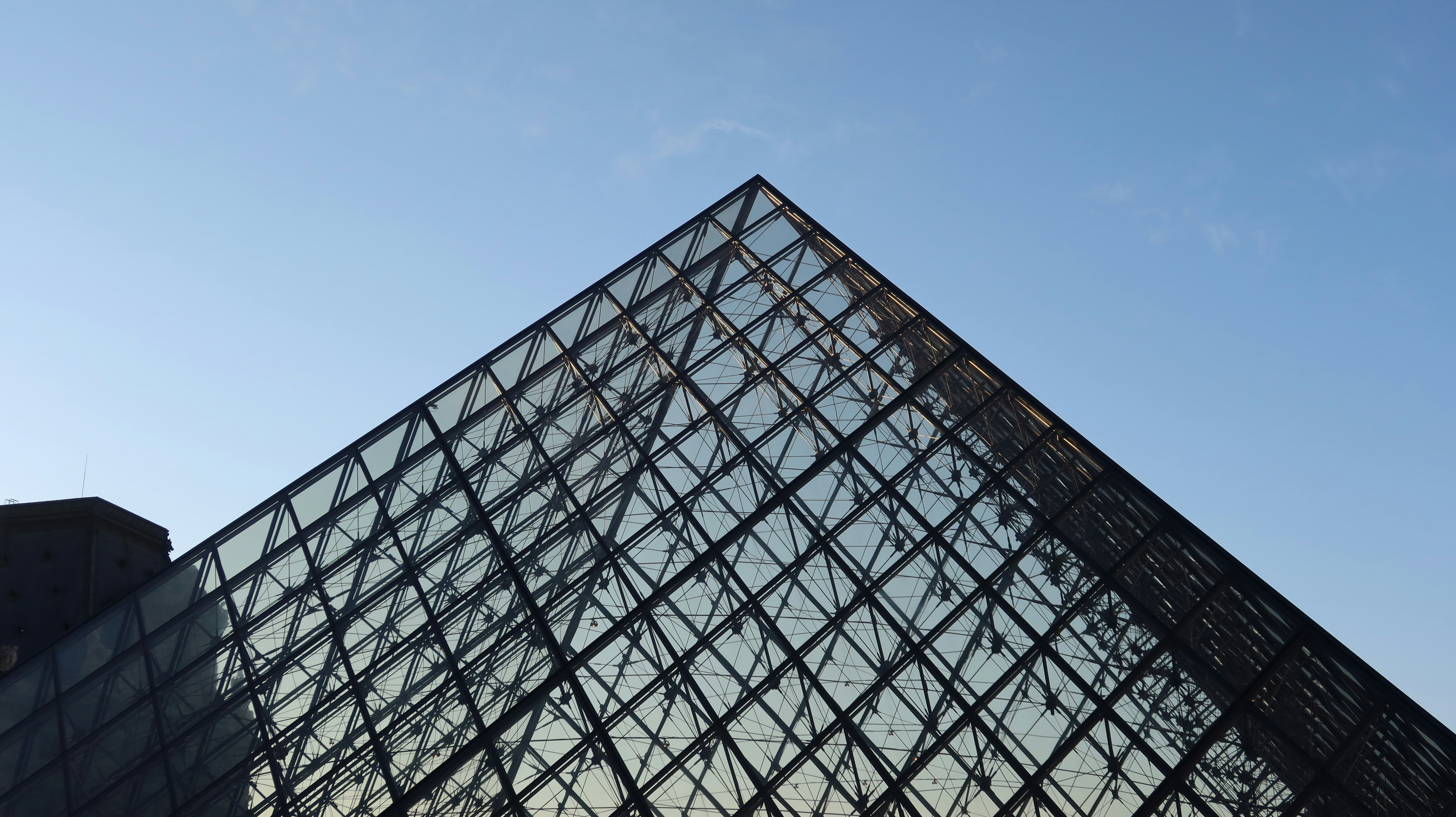 The louvre pyramid against a clear, blue sky.