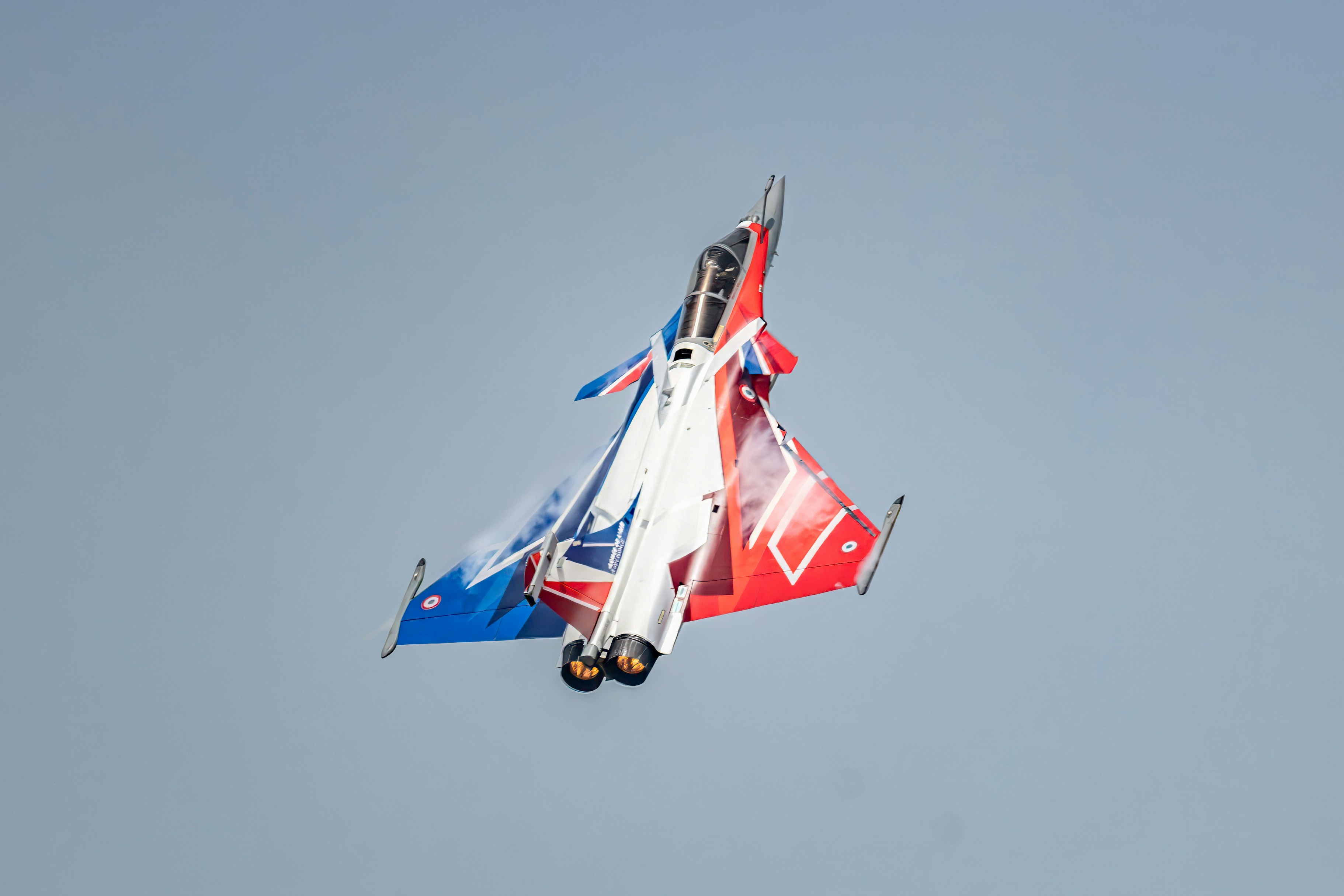 A fighter jet adorned with flags in the sky.