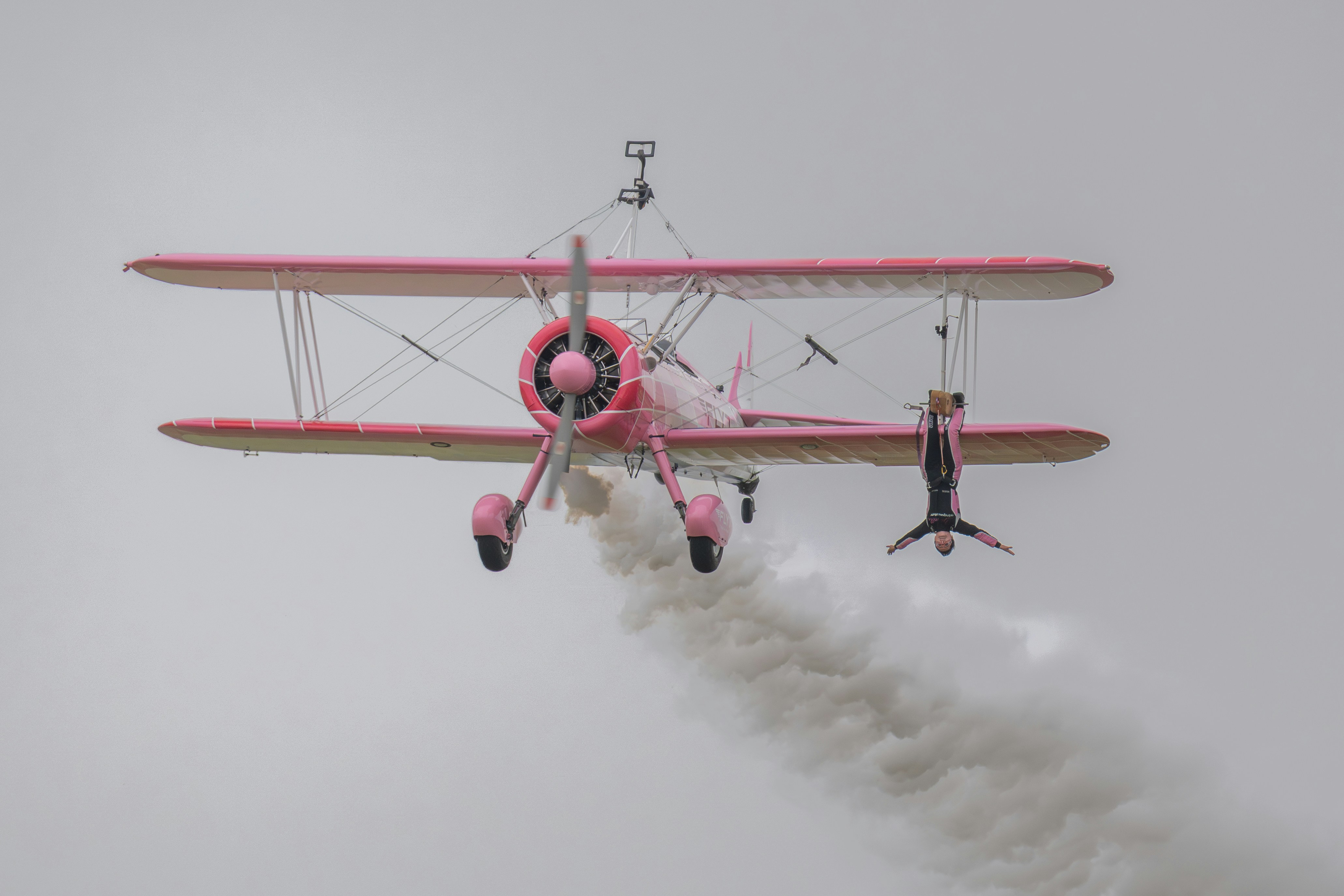 A pink biplane performs a smoke trail maneuver. photo – Free Human ...