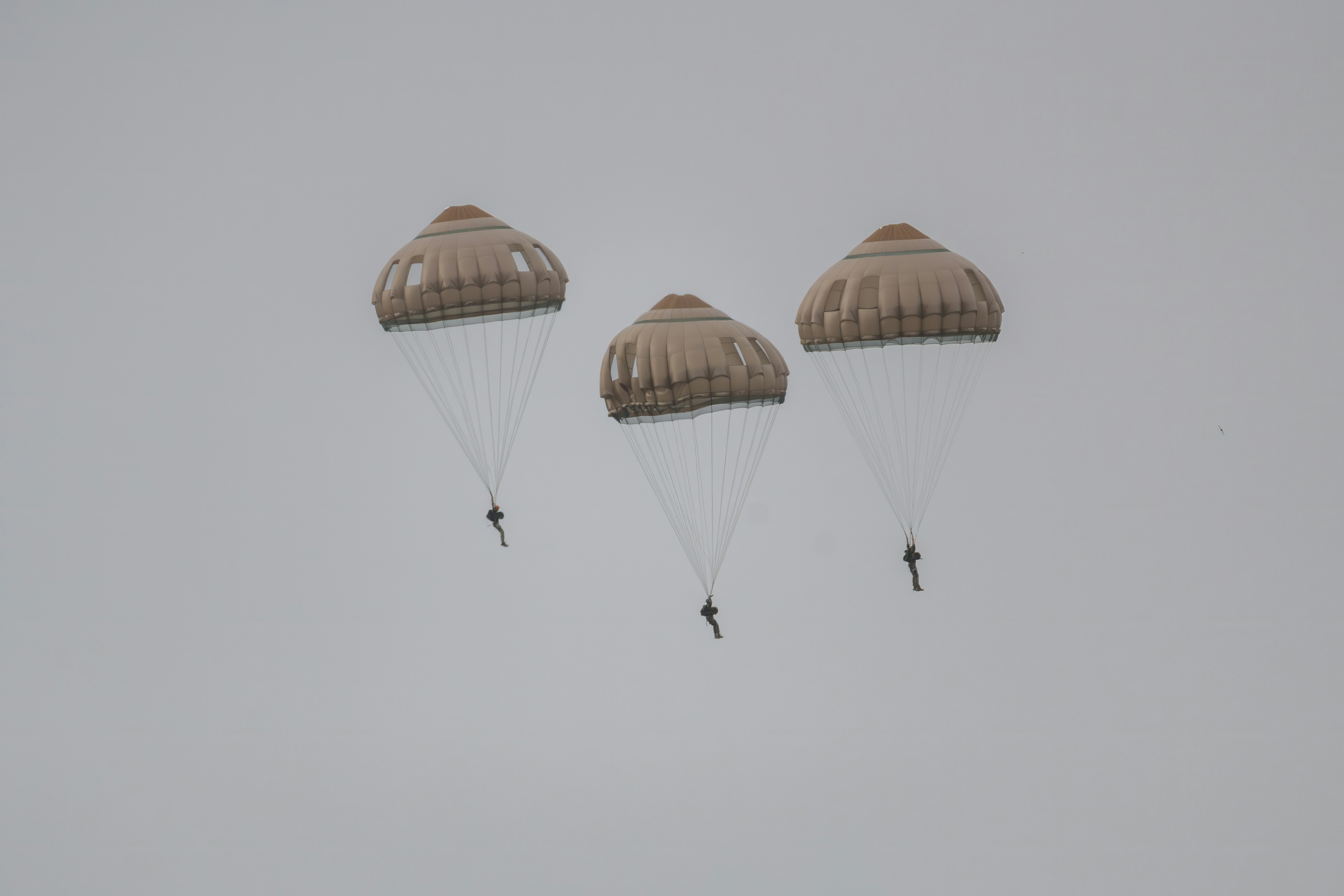 Triad of Skyward Descent: Parachutists in Uninhibited Ascent