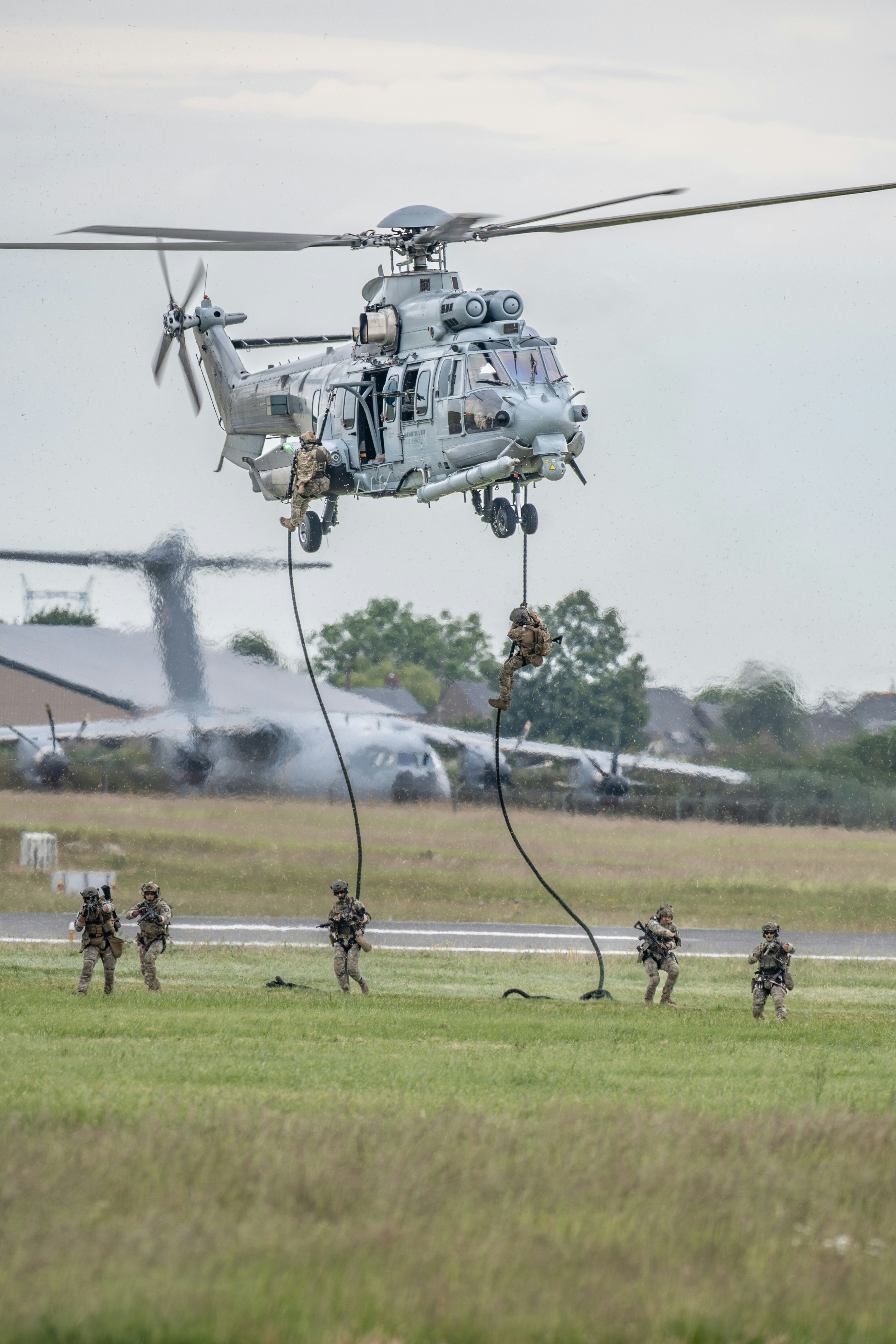 Military personnel conduct a tactical extraction drill with a helicopter, showcasing coordinated maneuvers and equipment deployment.