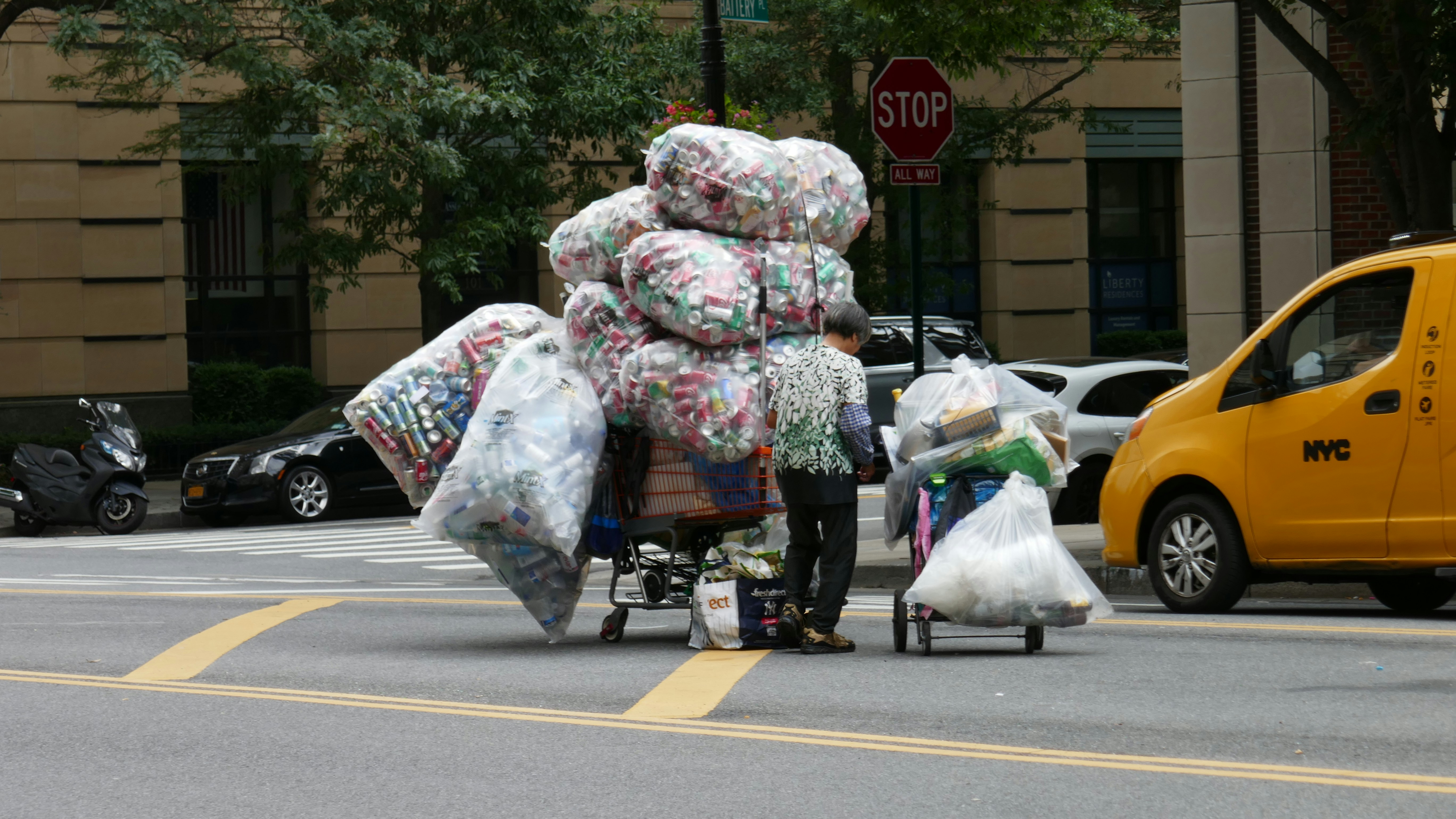 A person pushes a cart loaded with many bags.