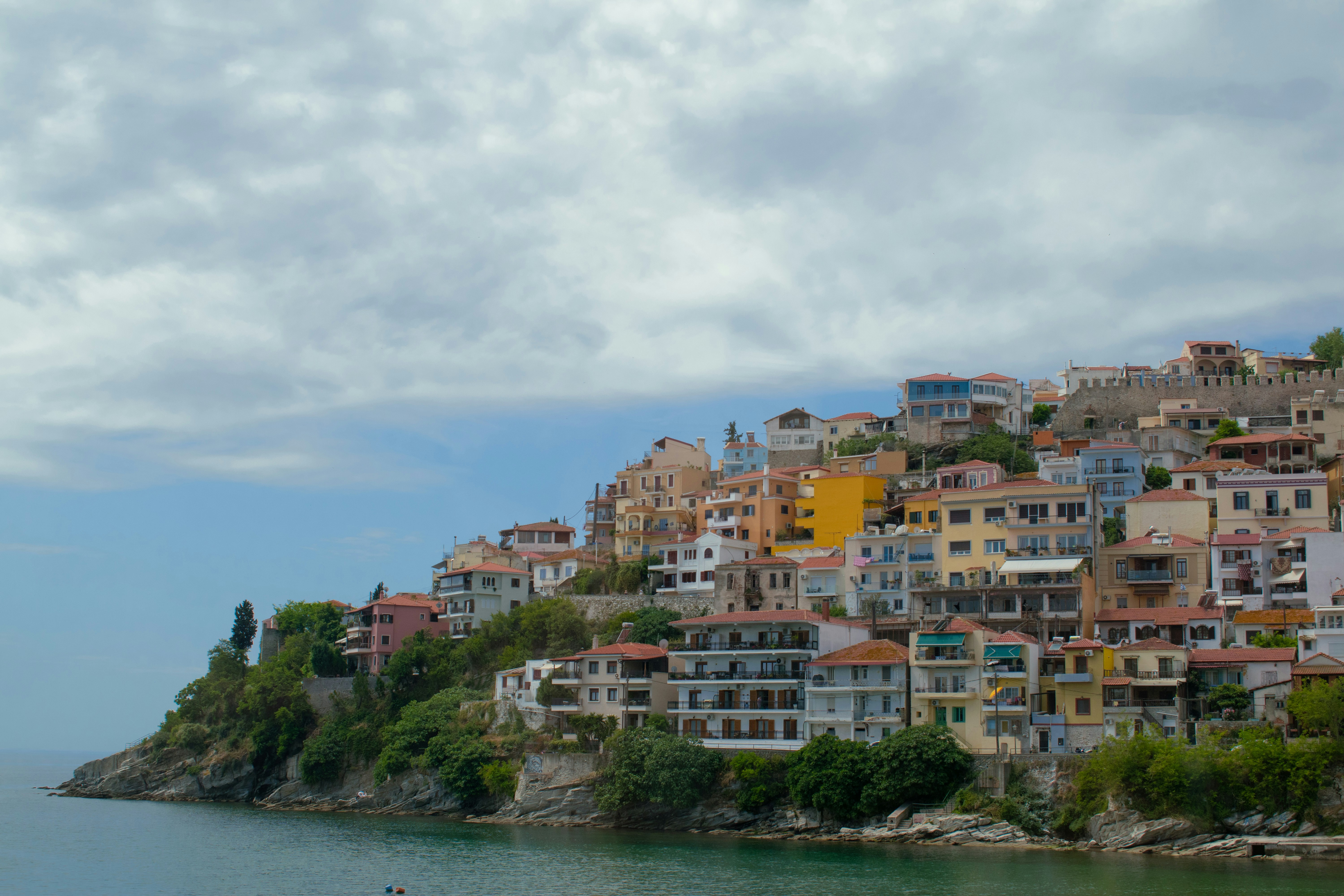 Vibrant hillside village overlooking a tranquil sea, showcasing a blend of architectural styles and colors. The scene captures the essence of coastal living.