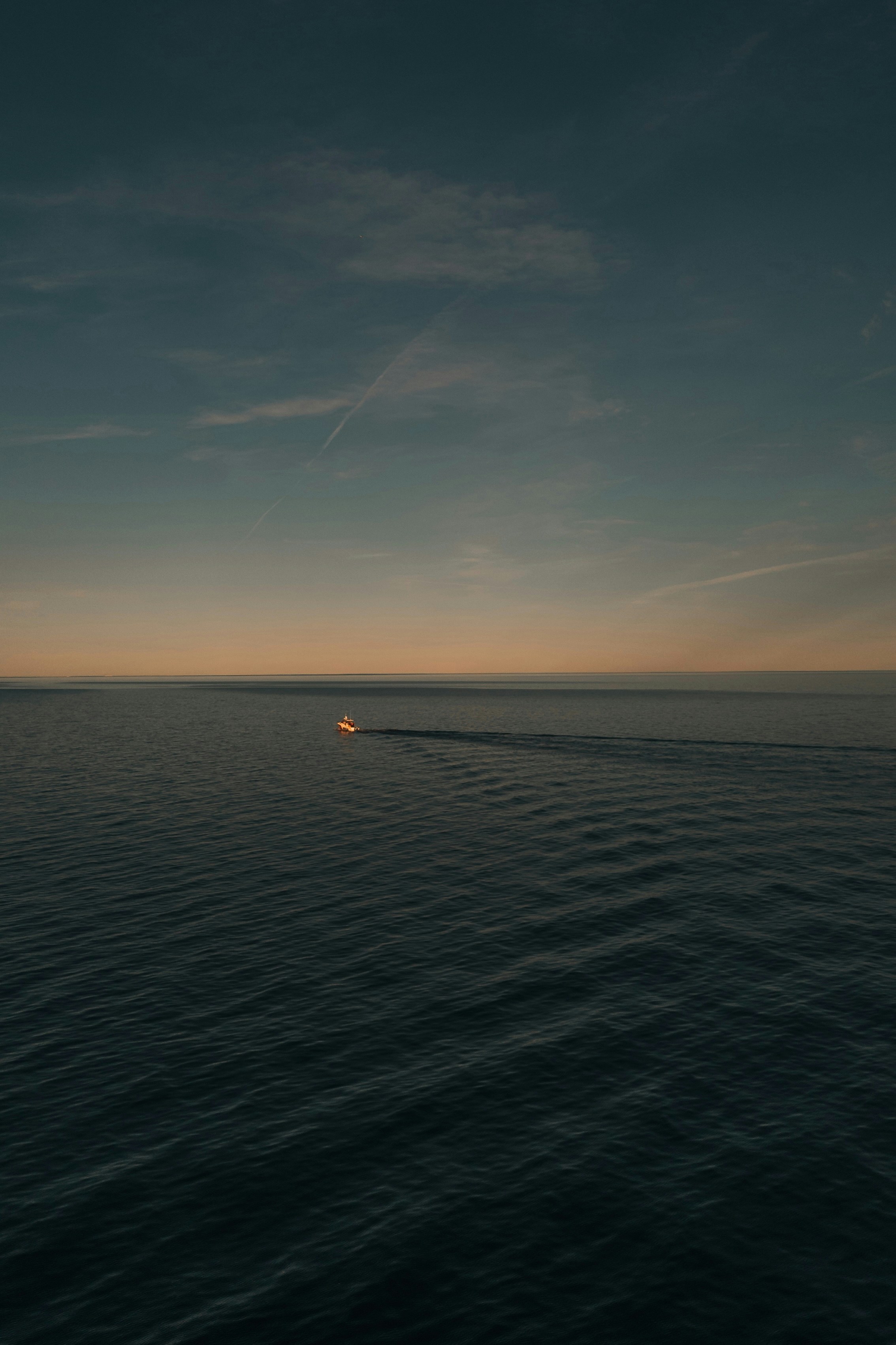 Cruising | A boat sails across the vast, dark ocean.