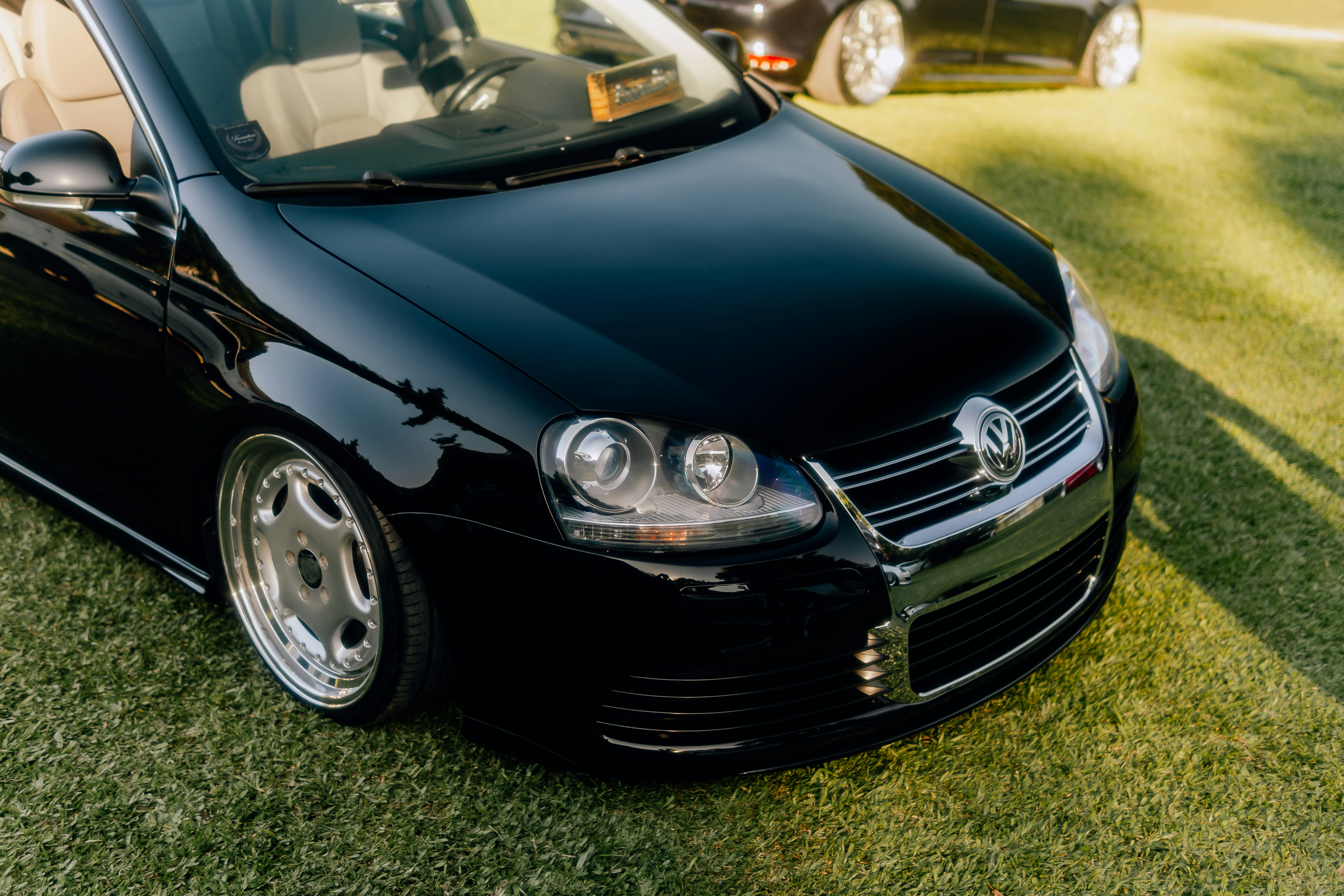 A shiny black car is parked on the grass. photo – Free Car Image on ...