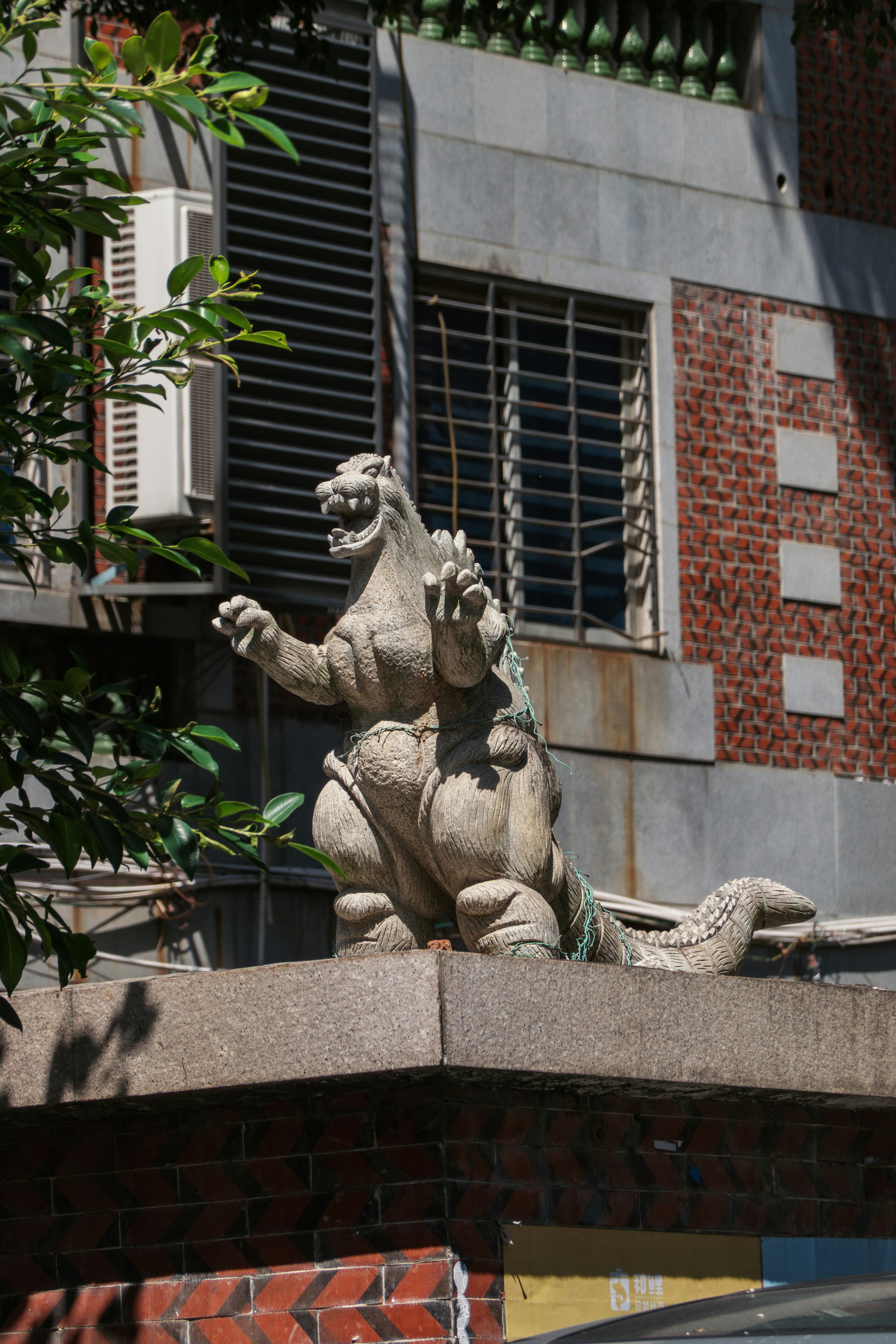Stone Guardian Overlooking the Street: a dragon statue framed by urban brick and greenery