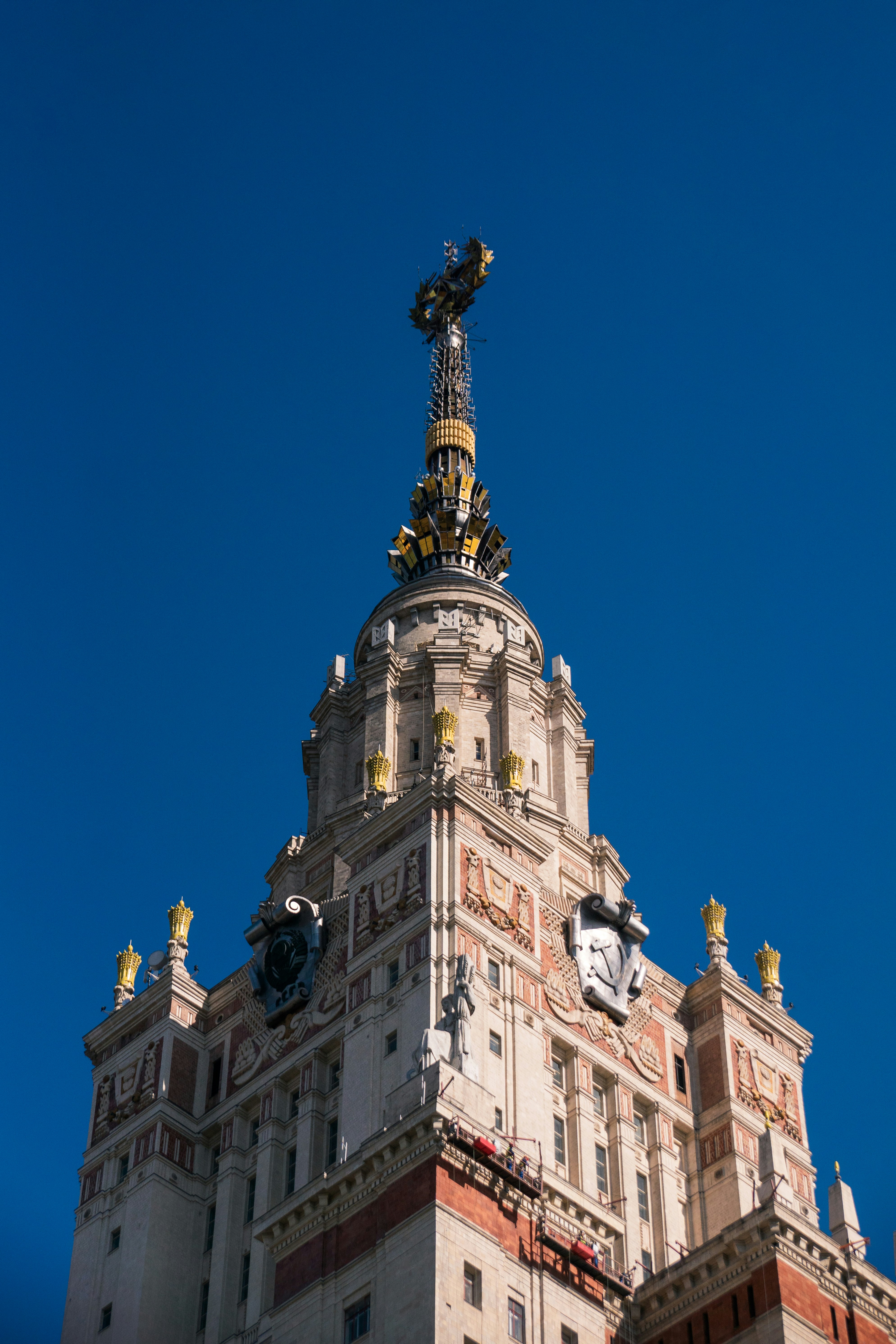 Ornate skyscraper adorned with gold accents and intricate sculptures against a clear blue sky.
