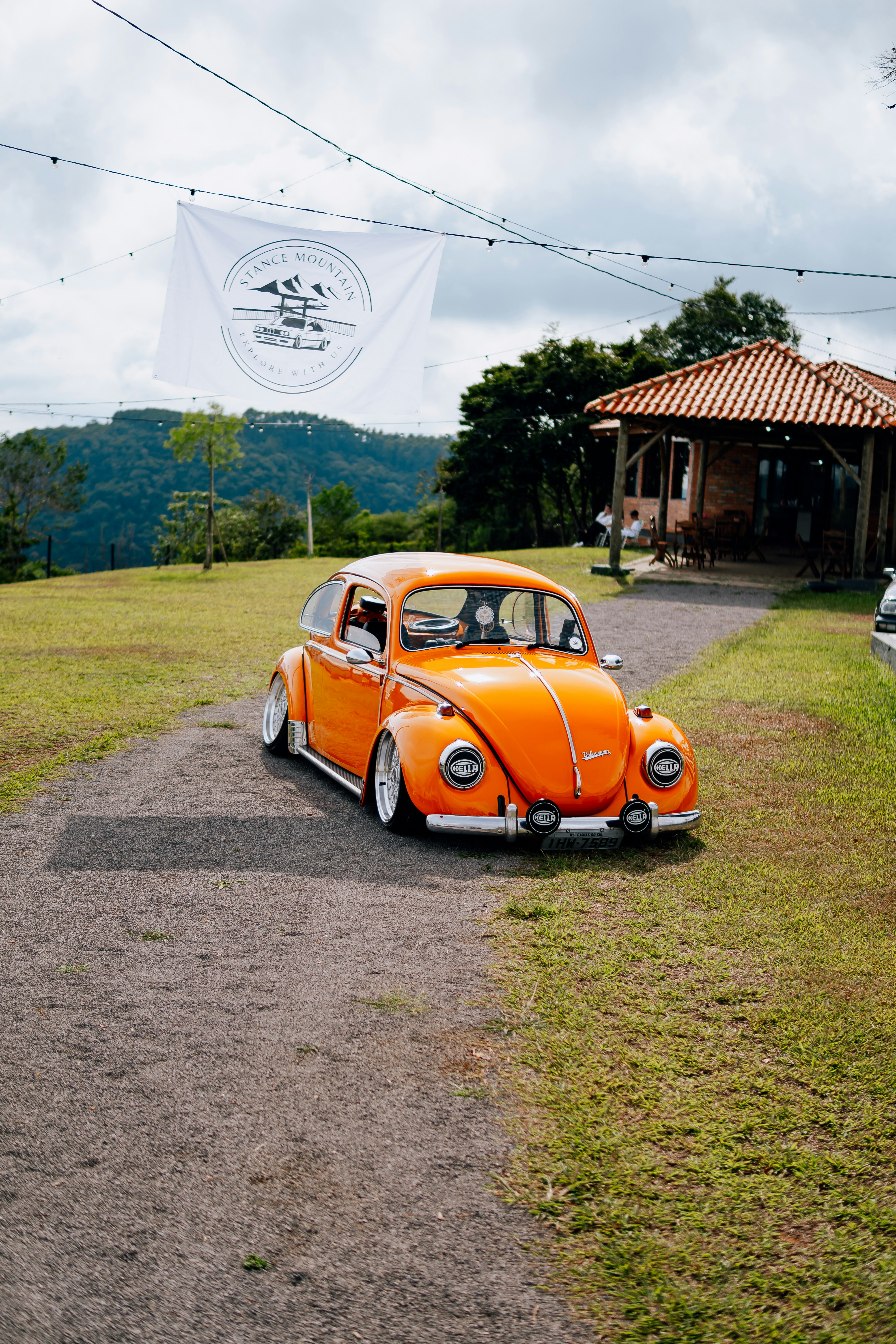 Orange VW Beetle on a Hilltop Gravel Path Beneath String Lights