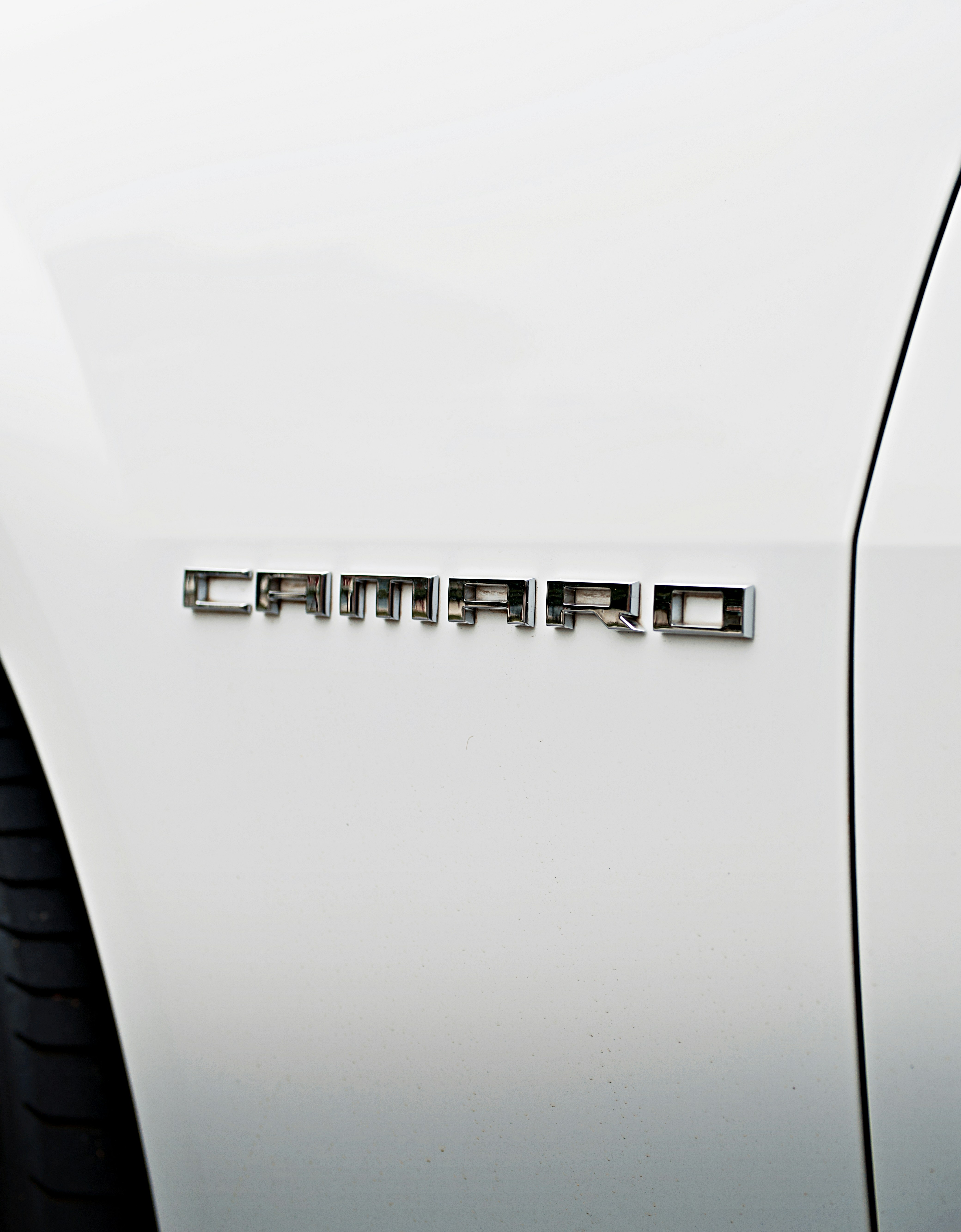 Chrome Camaro Emblem: Precision Reflections on a Pristine White Panel