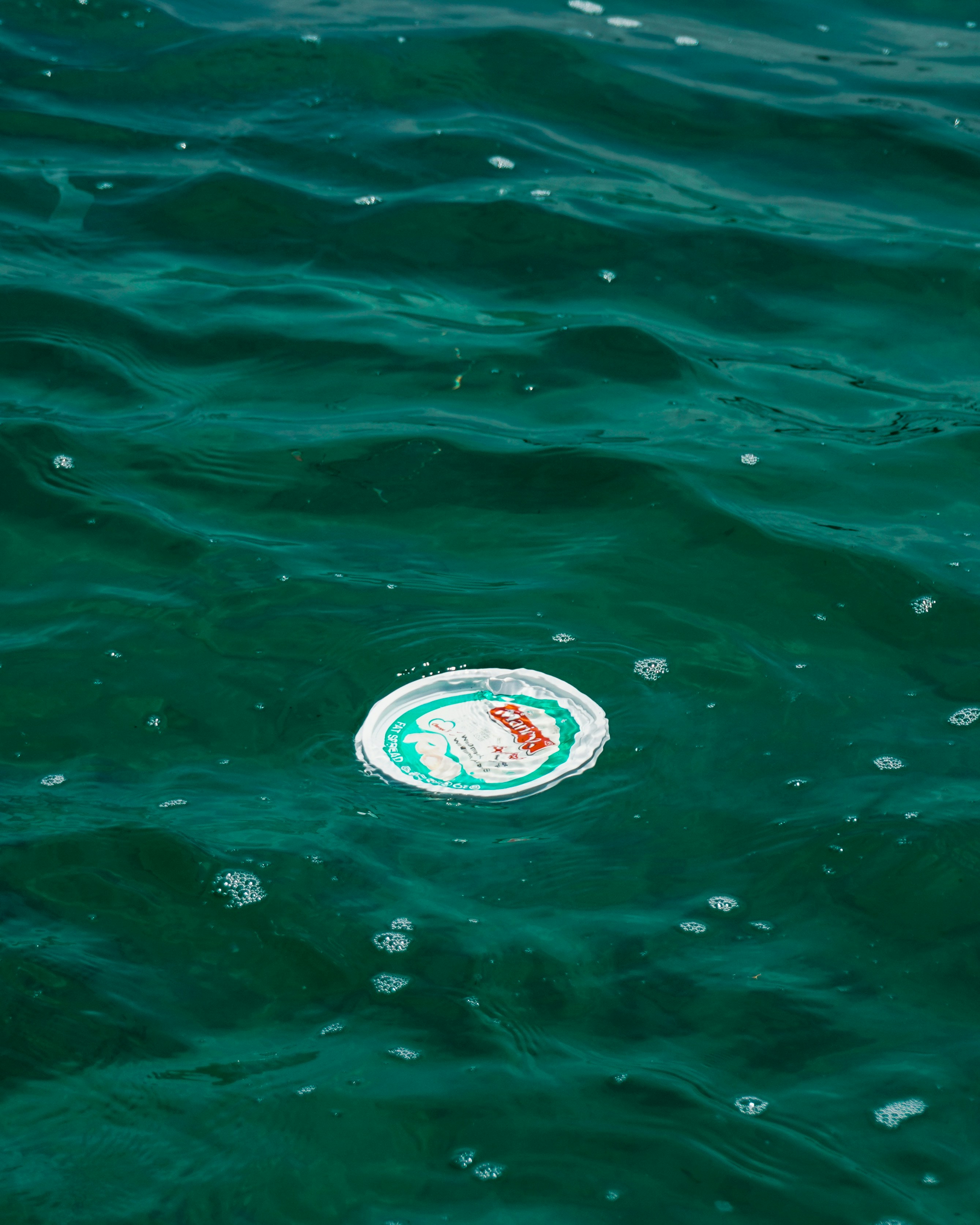 Adrift in Teal Currents: A Lone Bottle Cap Drifts Across the Surface