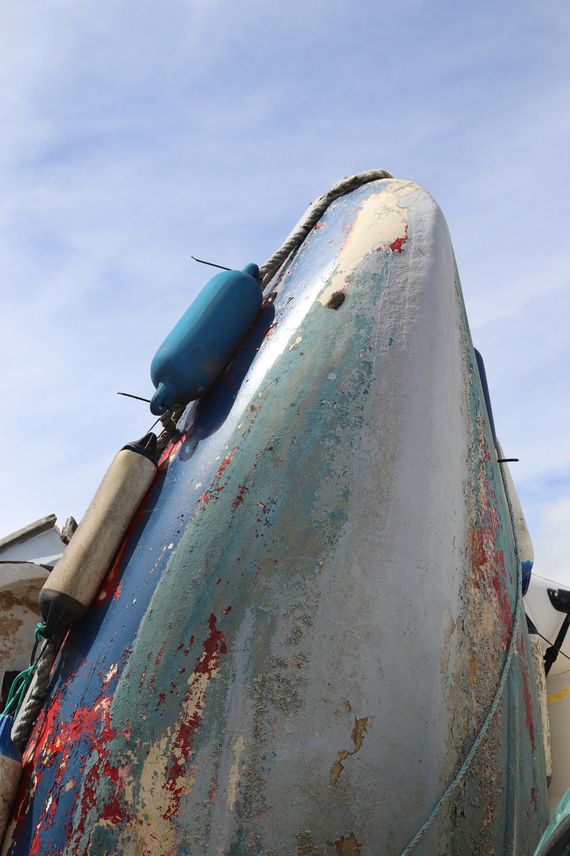 Vertical Vessel: a Salt-Streaked Hull with Peeling Paint against a Clear Sky