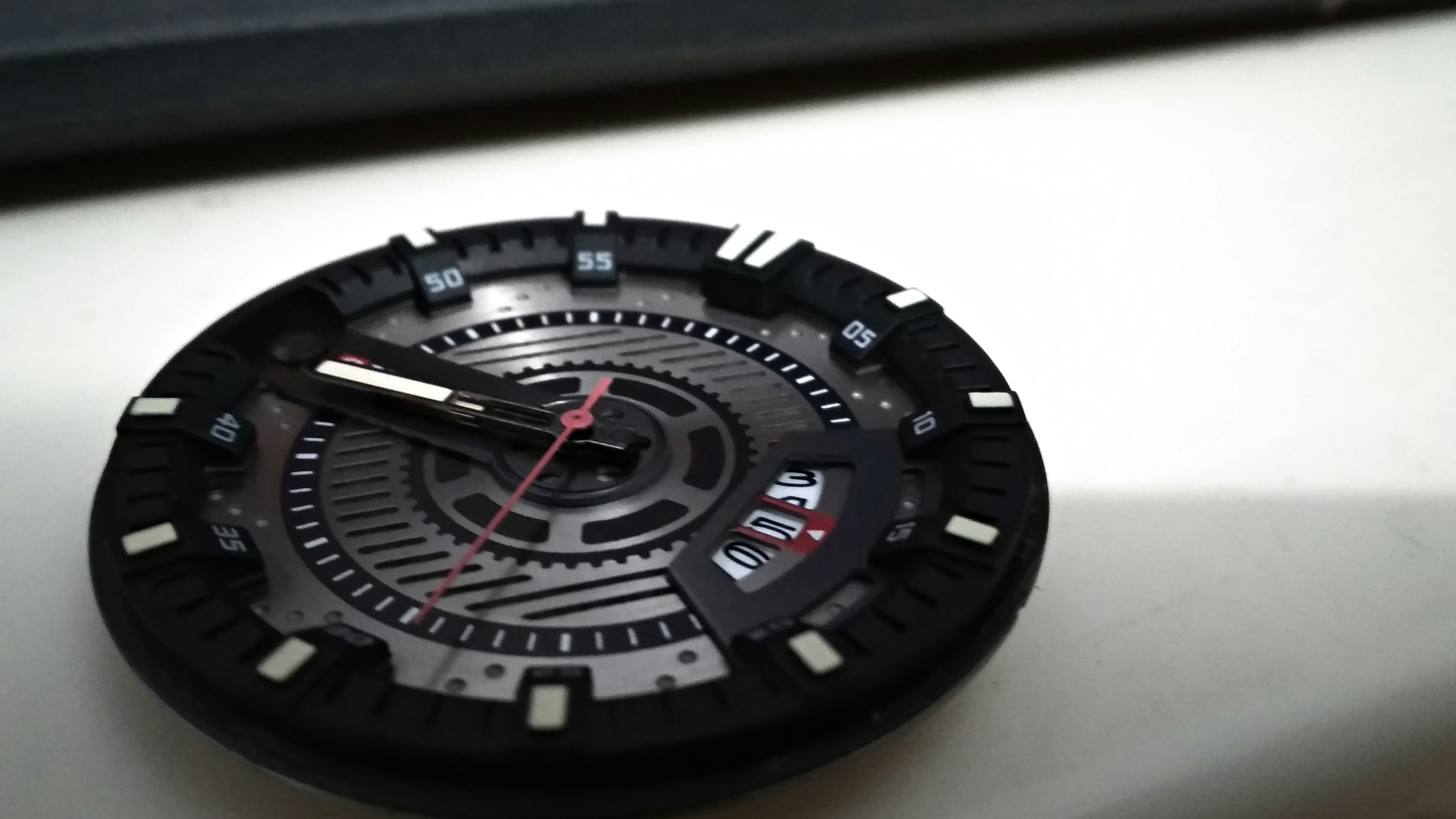 Detailed close-up of a sophisticated watch face featuring intricate design and bold markers. The interplay of light highlights its mechanical features.