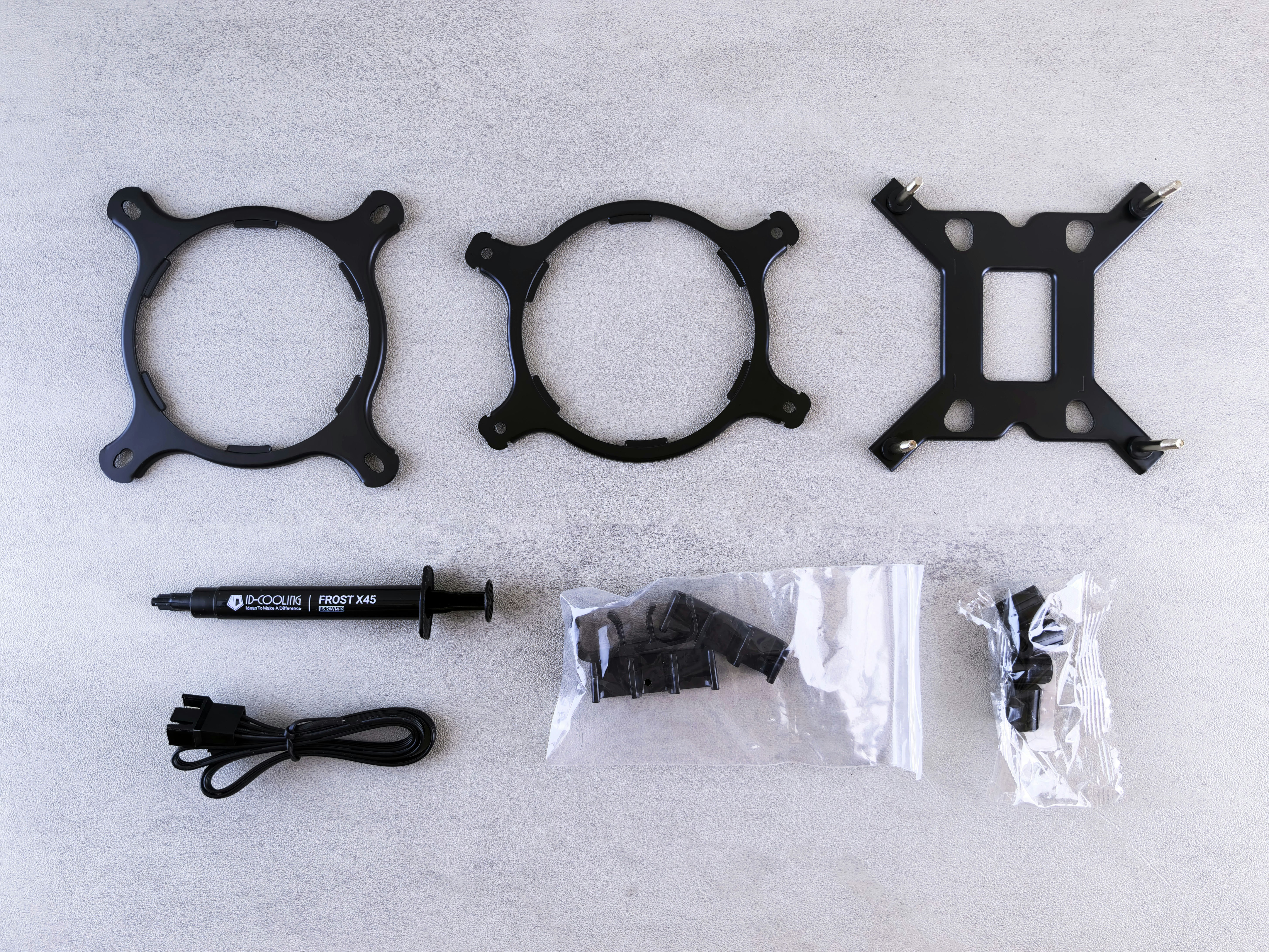 Assembly parts including mounting brackets, a thermal paste applicator, and connectors arranged neatly on a light surface.