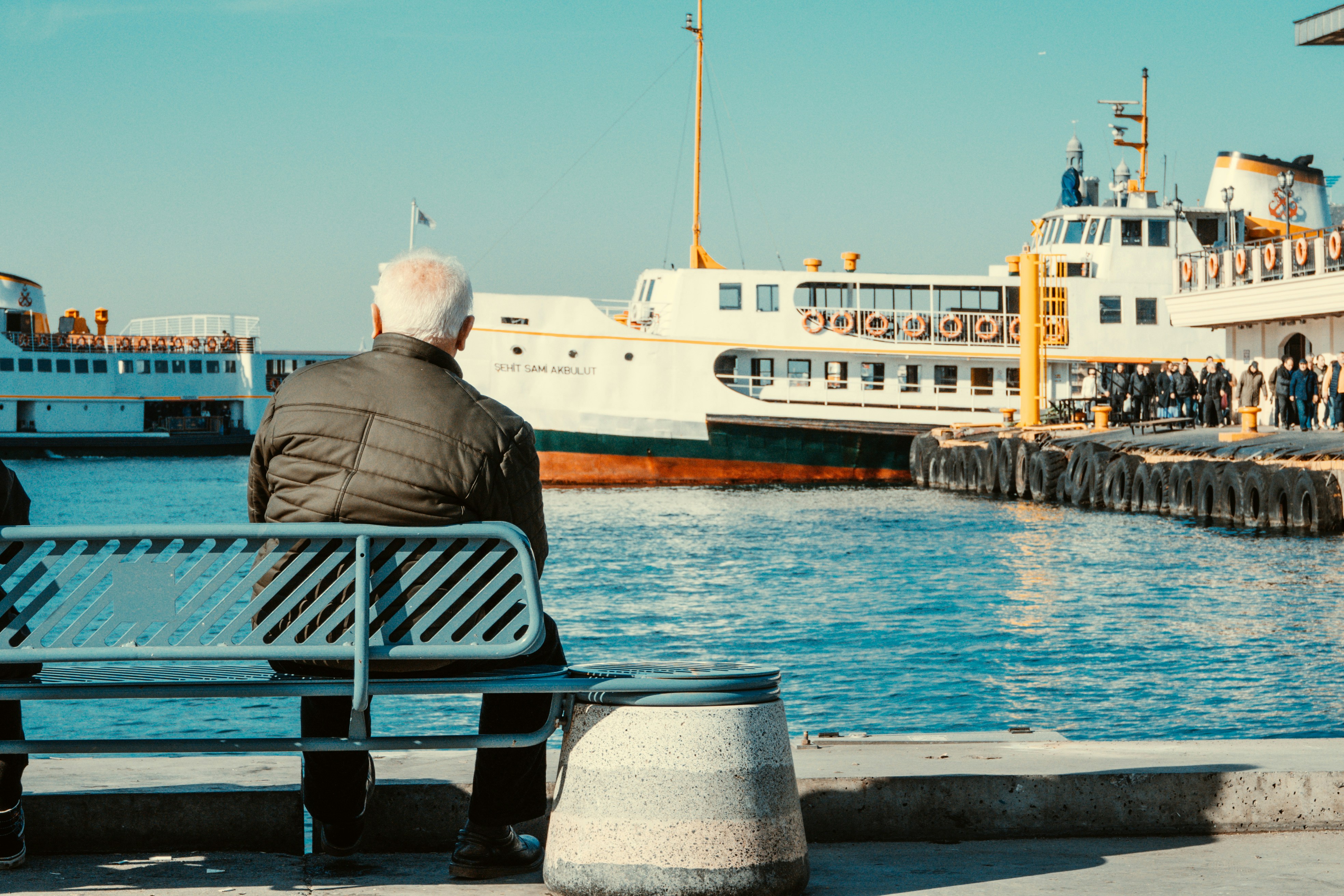 A man sits, watching boats at the dock. photo – Free Blue Image on Unsplash