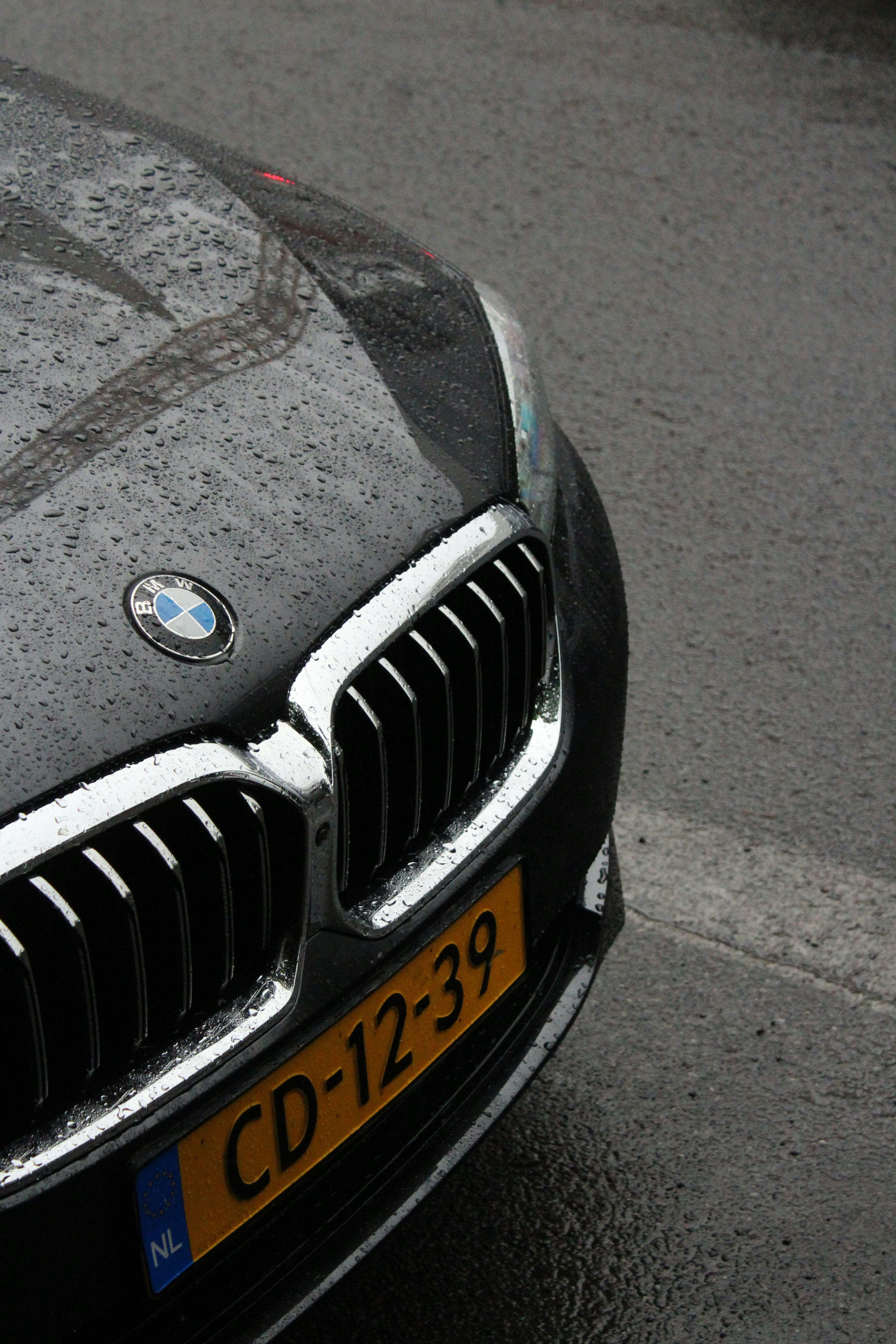 BMW 5 series ; Diplomatic car in the Brussels with the Netherlands license plate | A wet BMW car sits on a rainy day.