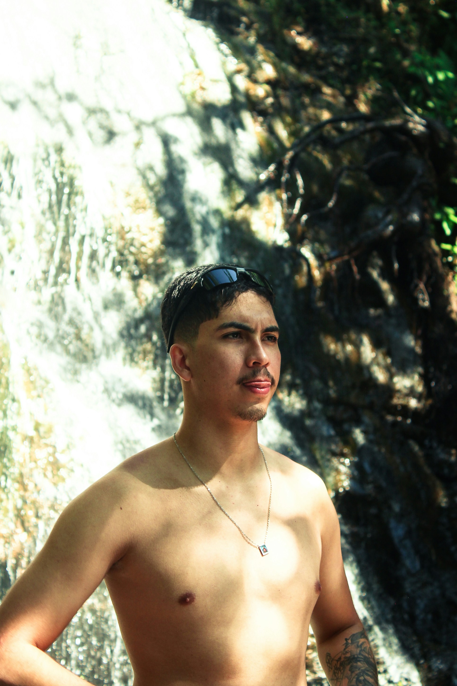 @gleid_j | Man stands shirtless near a waterfall.