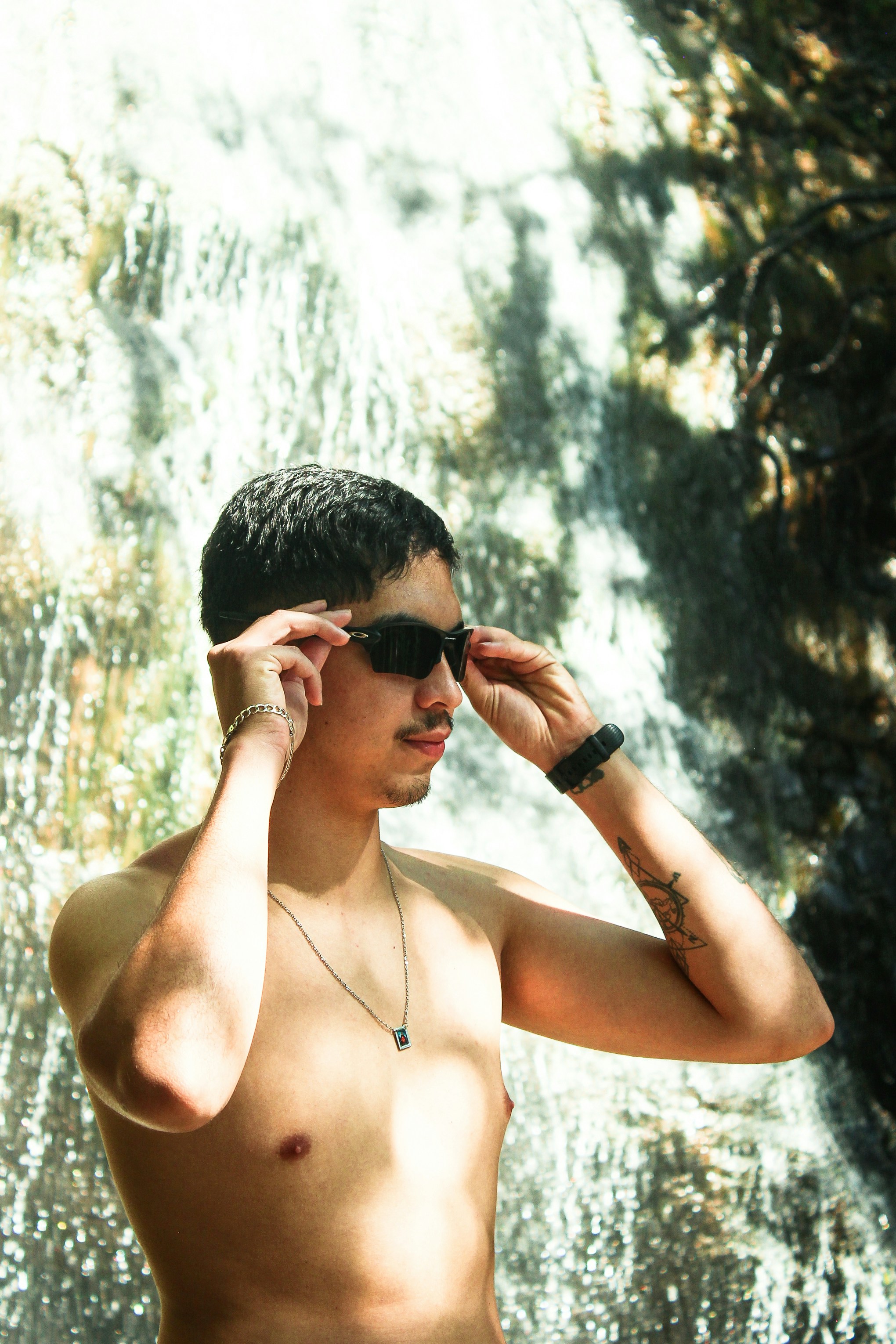 @gleid_j | Man adjusts sunglasses in front of a waterfall.