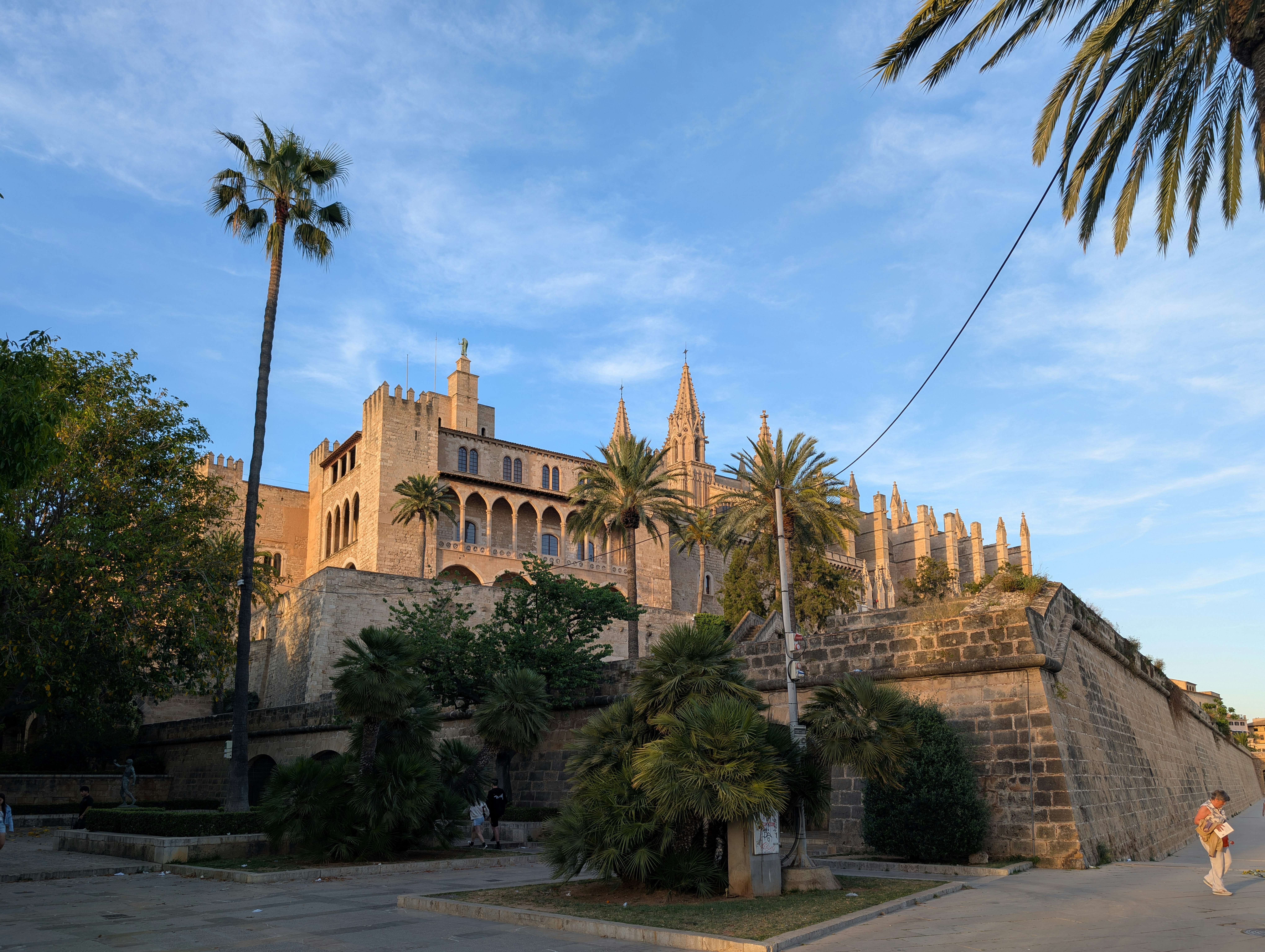 Historic castle set against a vibrant sky, surrounded by lush palm trees and greenery. The scene captures the essence of architectural grandeur.