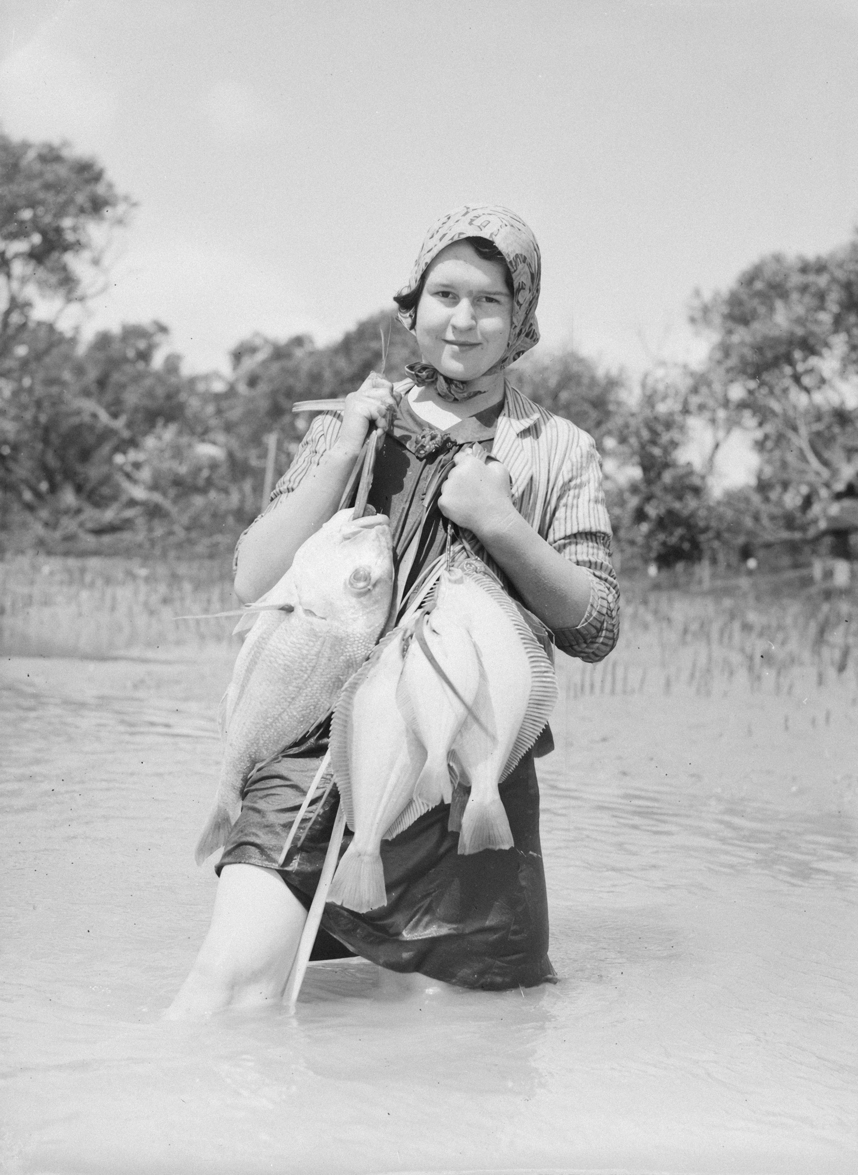 Riverbank Harvest: A Girl in Waders Carries Two Ducks in Quiet Water